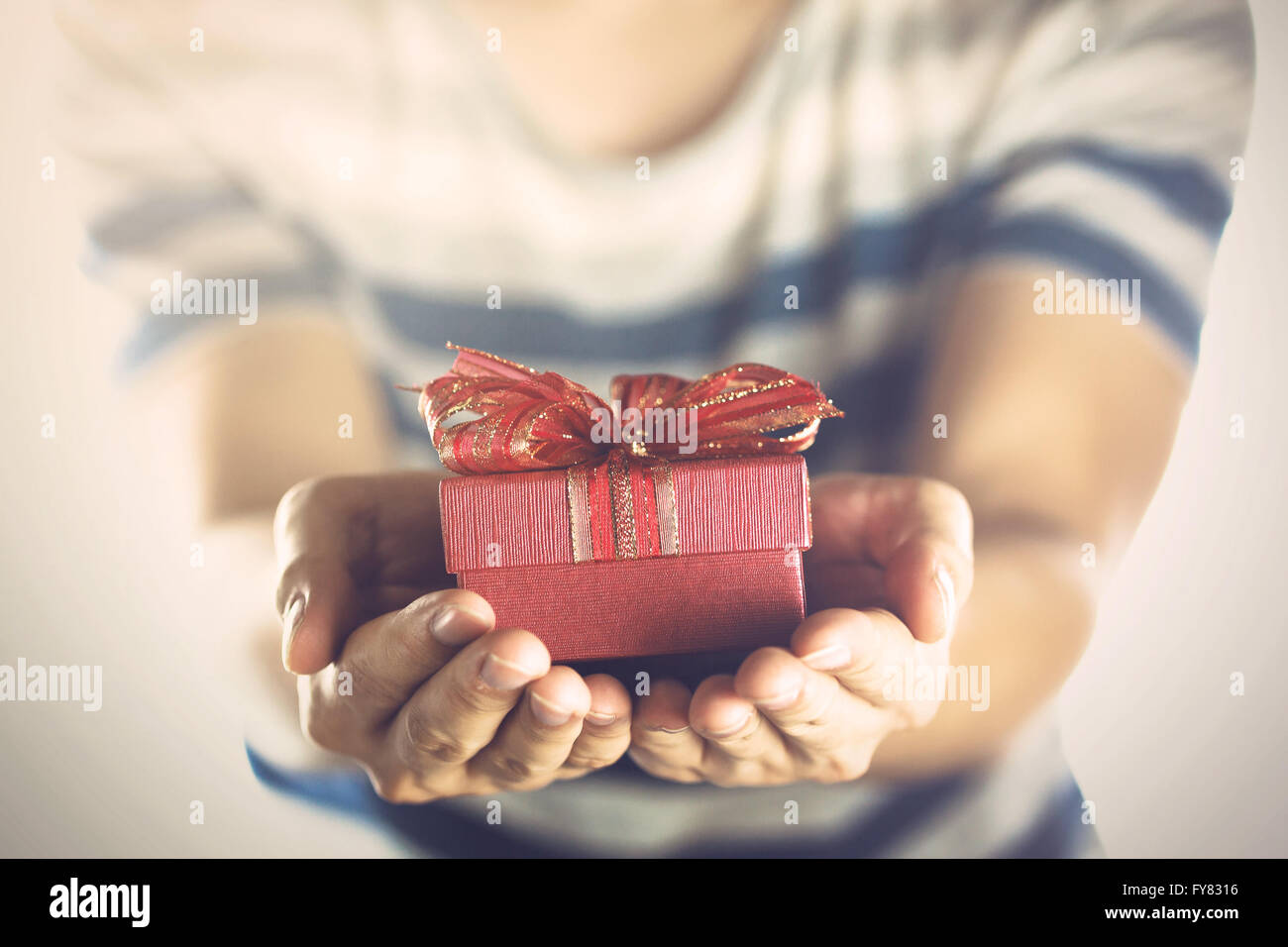Young man giving and presenting a gift to someone Stock Photo - Alamy