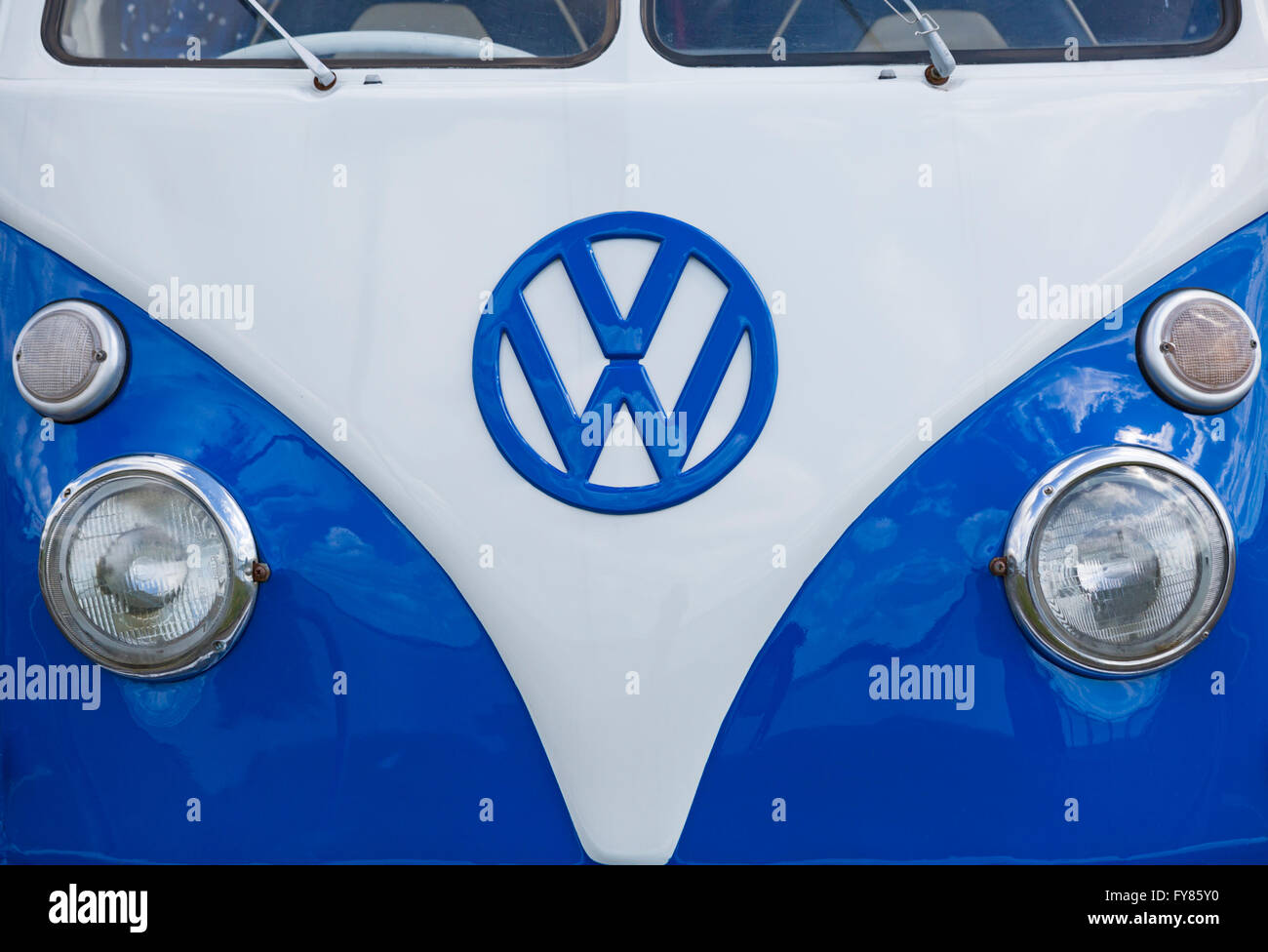 Detail of logo and lights on front of blue and white VW campervan ...