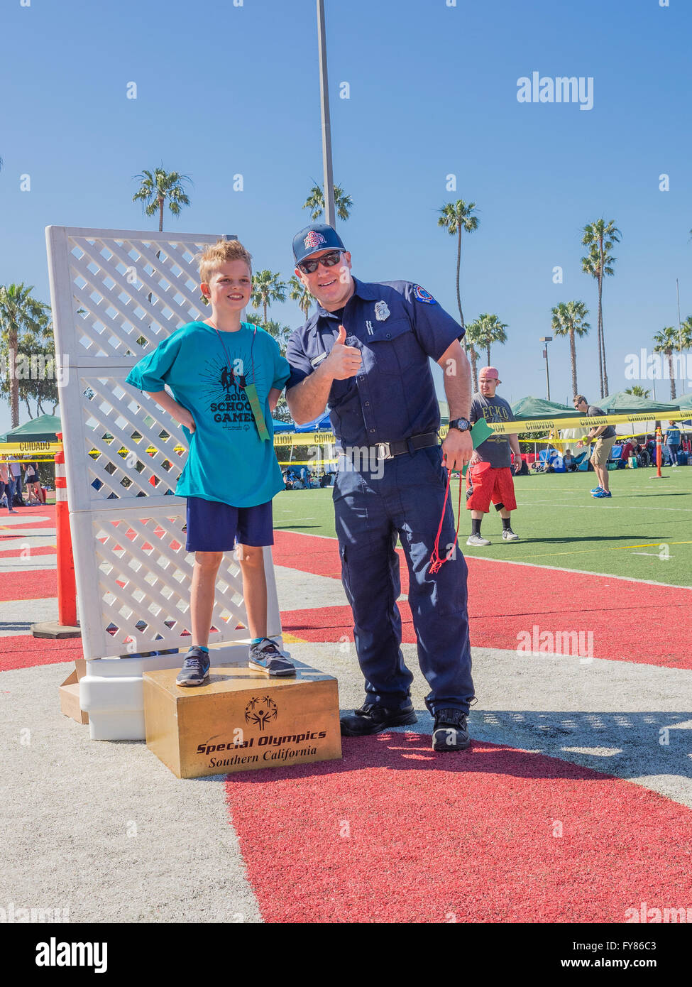 A disabled young boy 10-12 receives his award from a uniformed fireman ...
