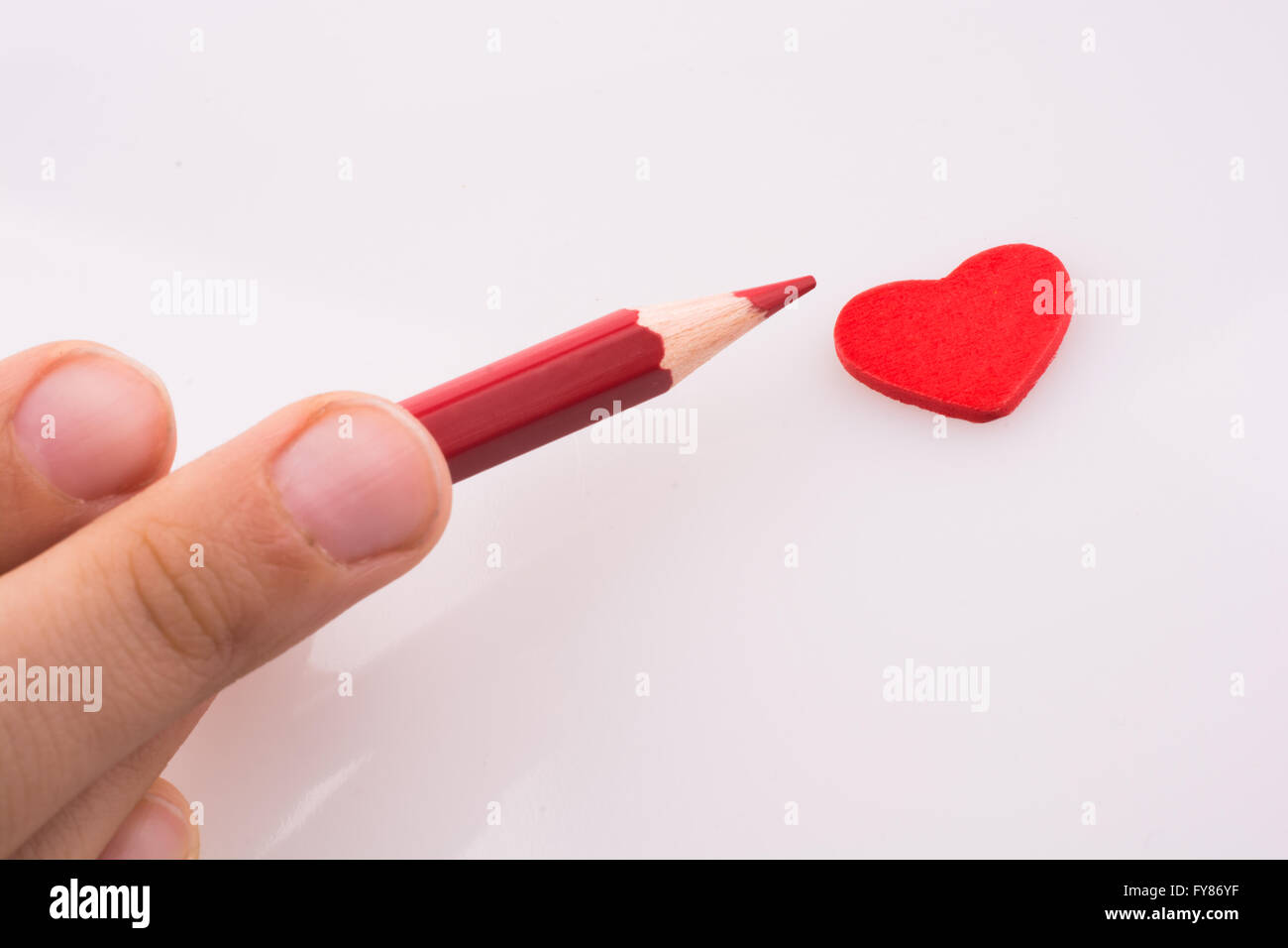 Pencil pointing a red heart Stock Photo - Alamy