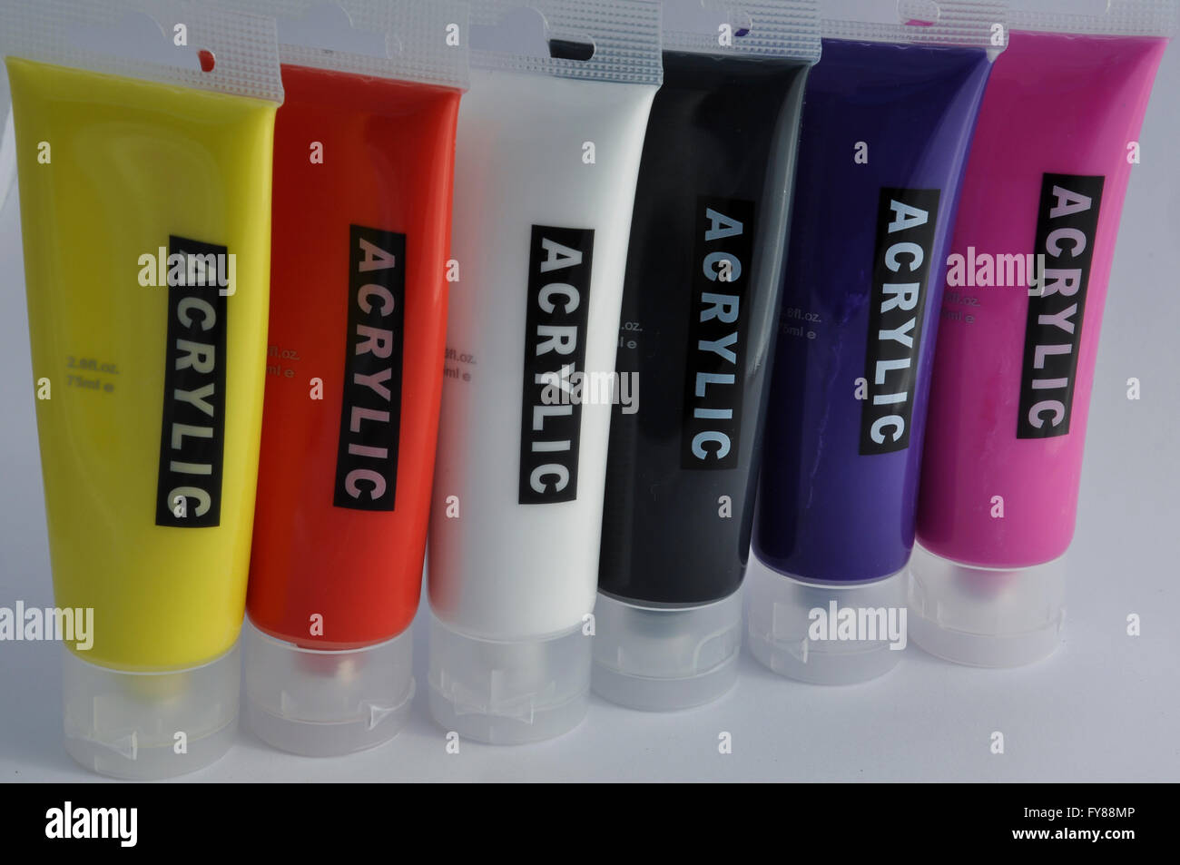 Multicoloured acrylic paint in a plastic tub on a white background ...