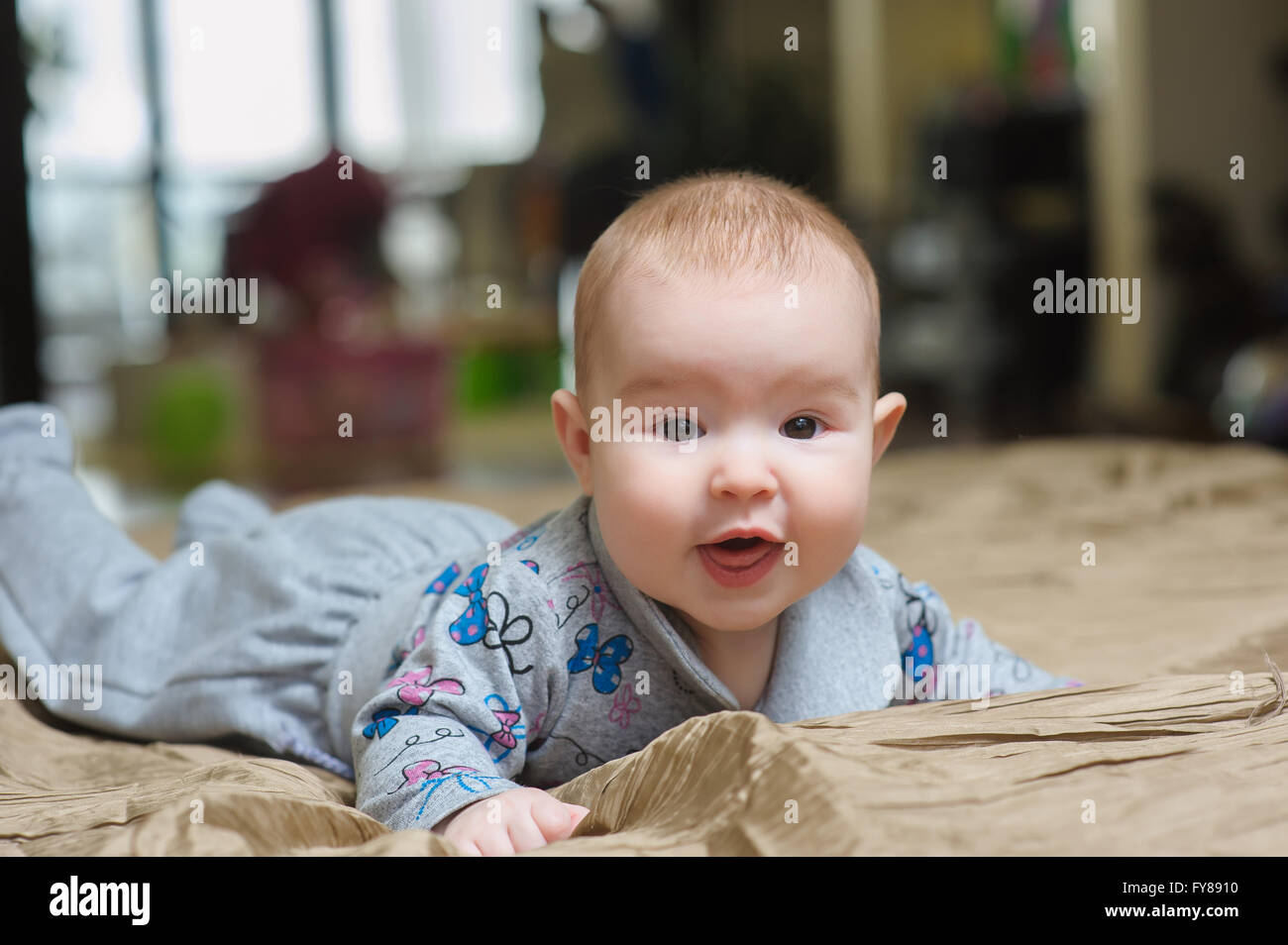 Baby girl lying on belly and grimacing Stock Photo - Alamy