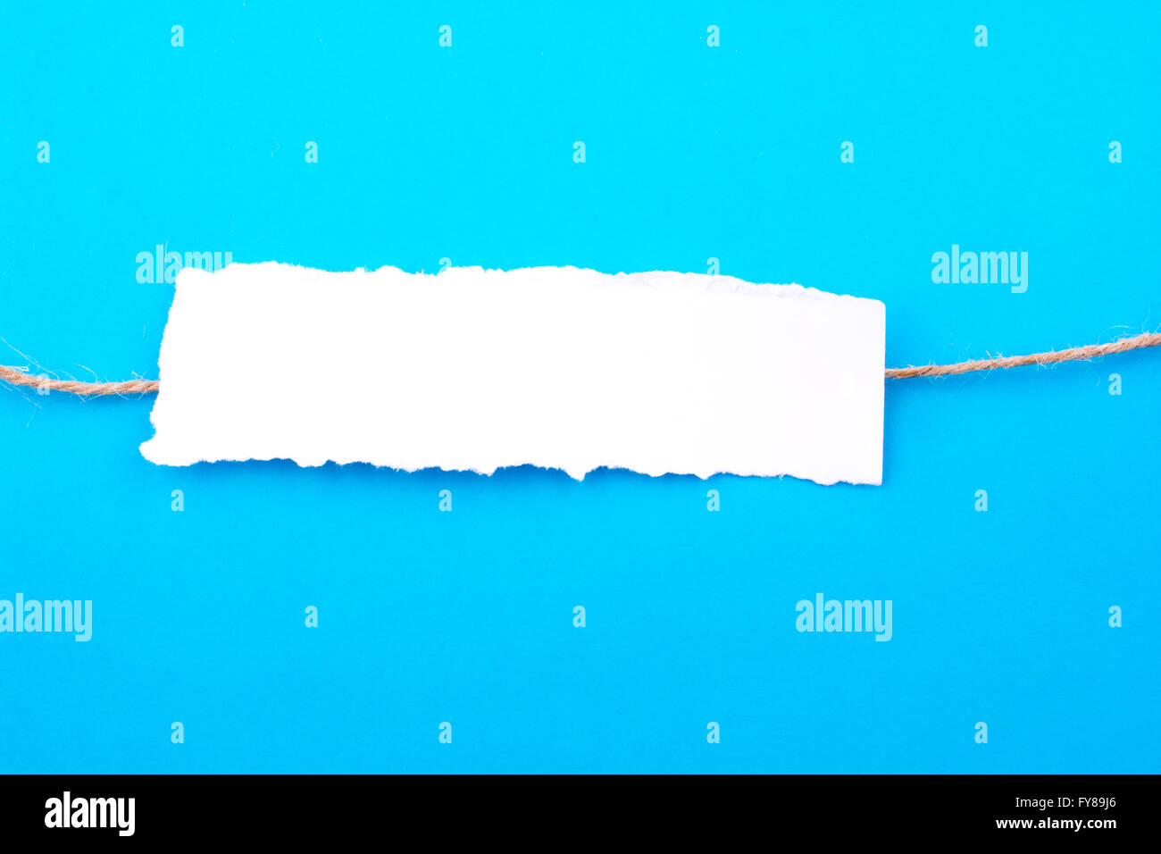 White paper note on a thread on blue background Stock Photo - Alamy