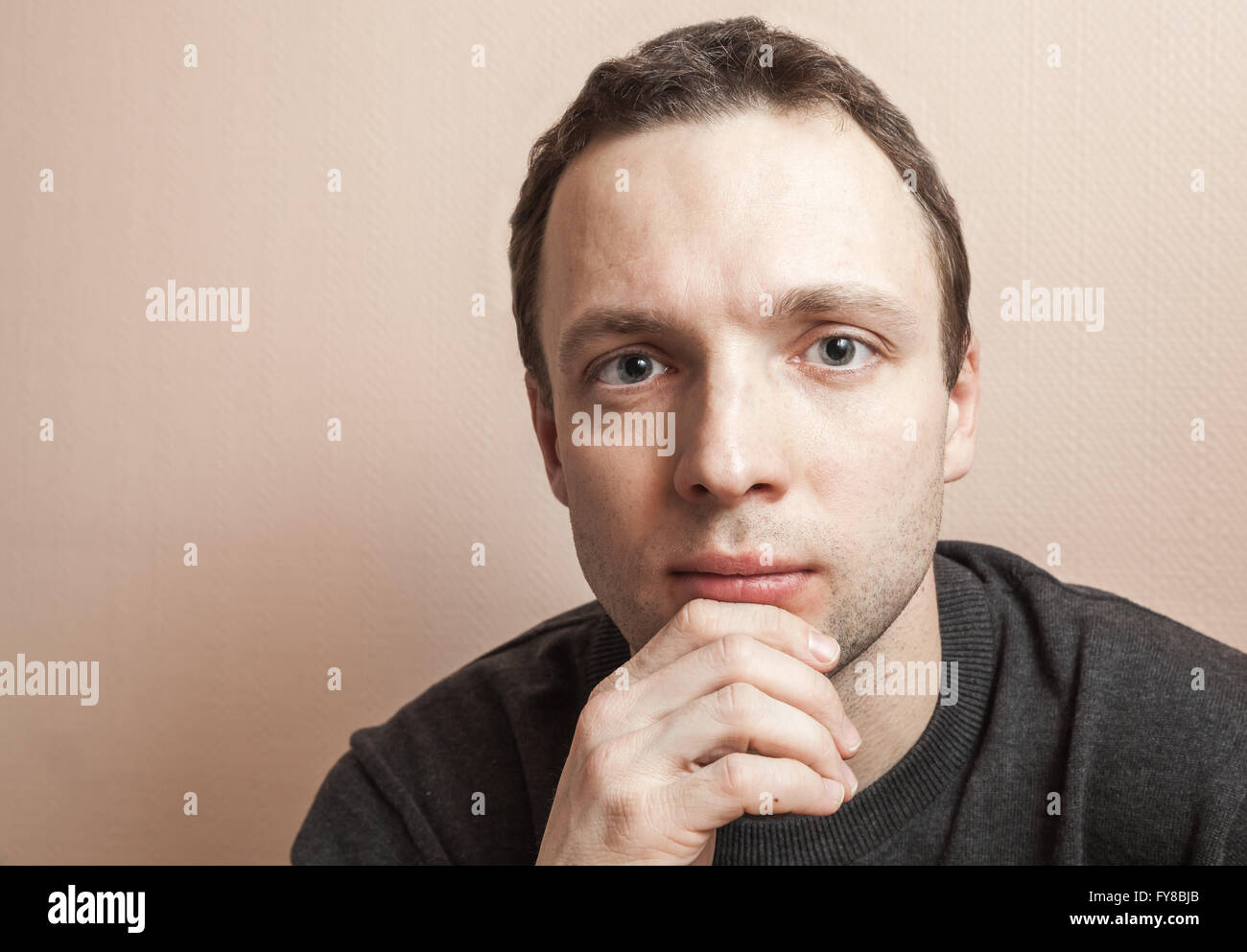 Young serious man, closeup studio portrait over gray wall background ...