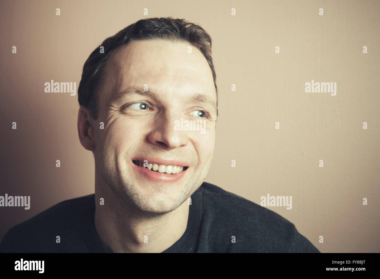 Young handsome positive Caucasian man, portrait over gray wall ...