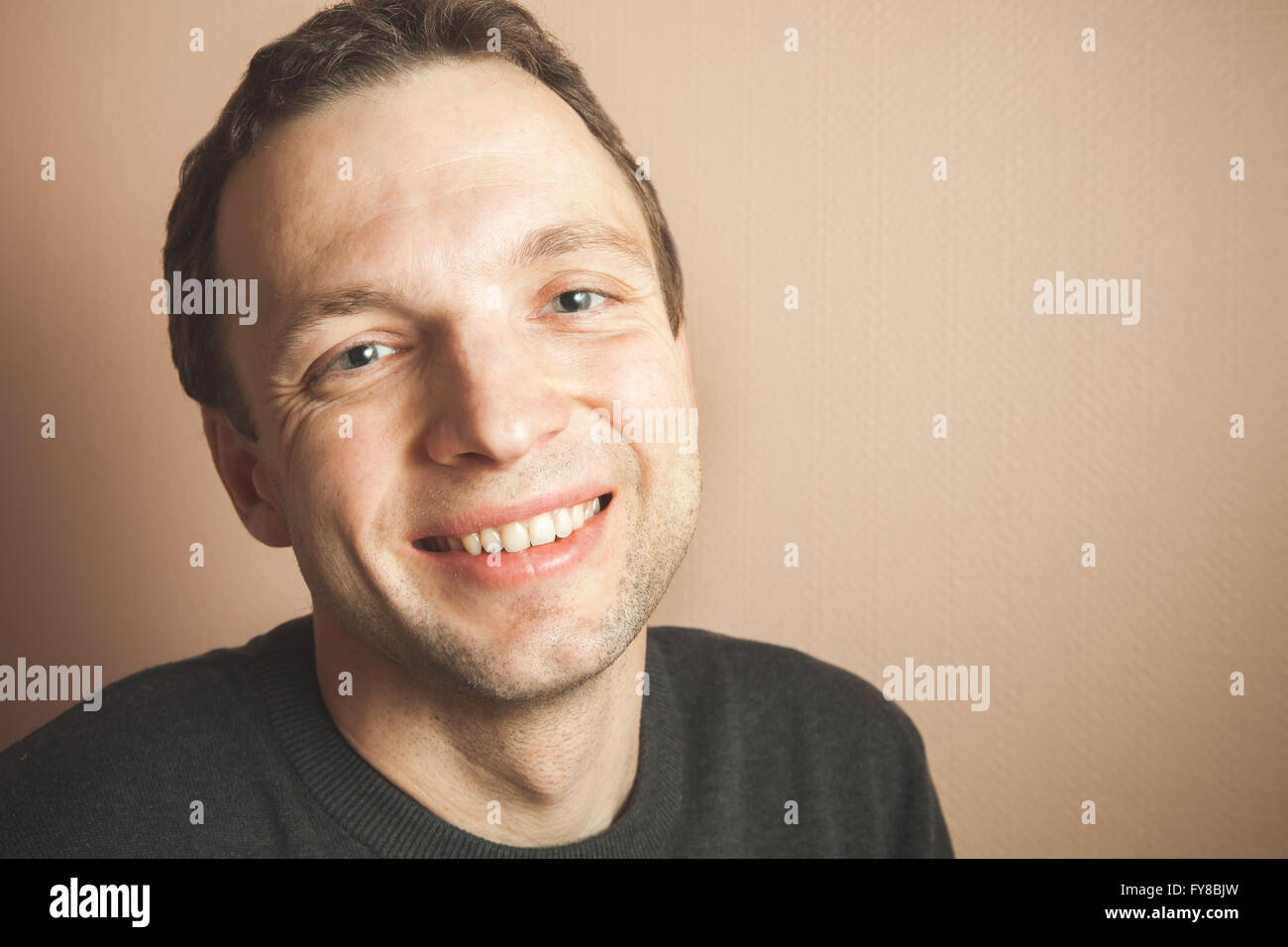 Young handsome smiling man studio portrait over gray wall background ...