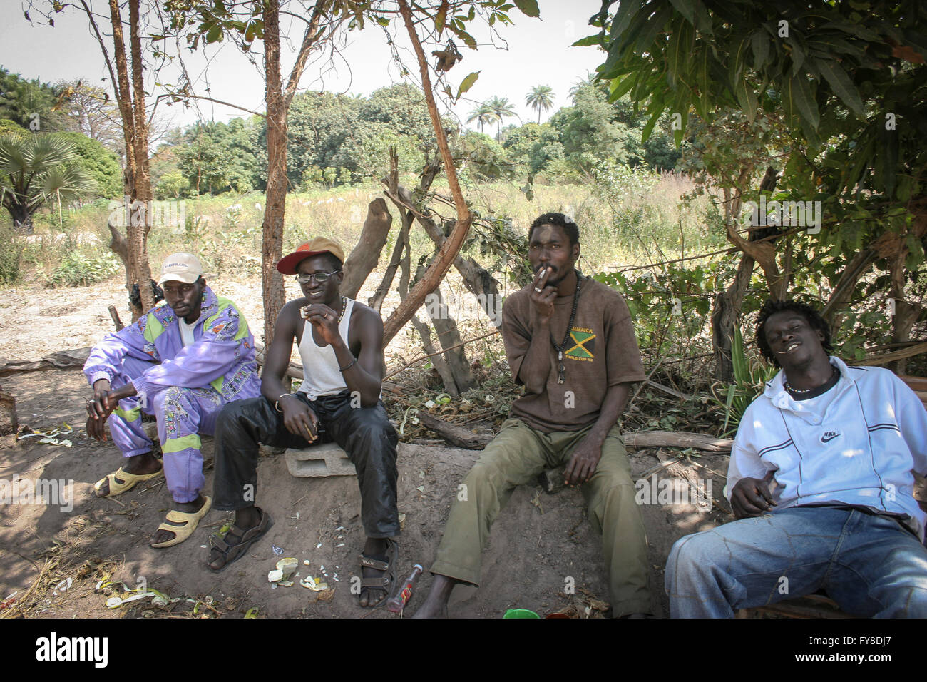 African young men chilling out while one of them is smoking a joint ...