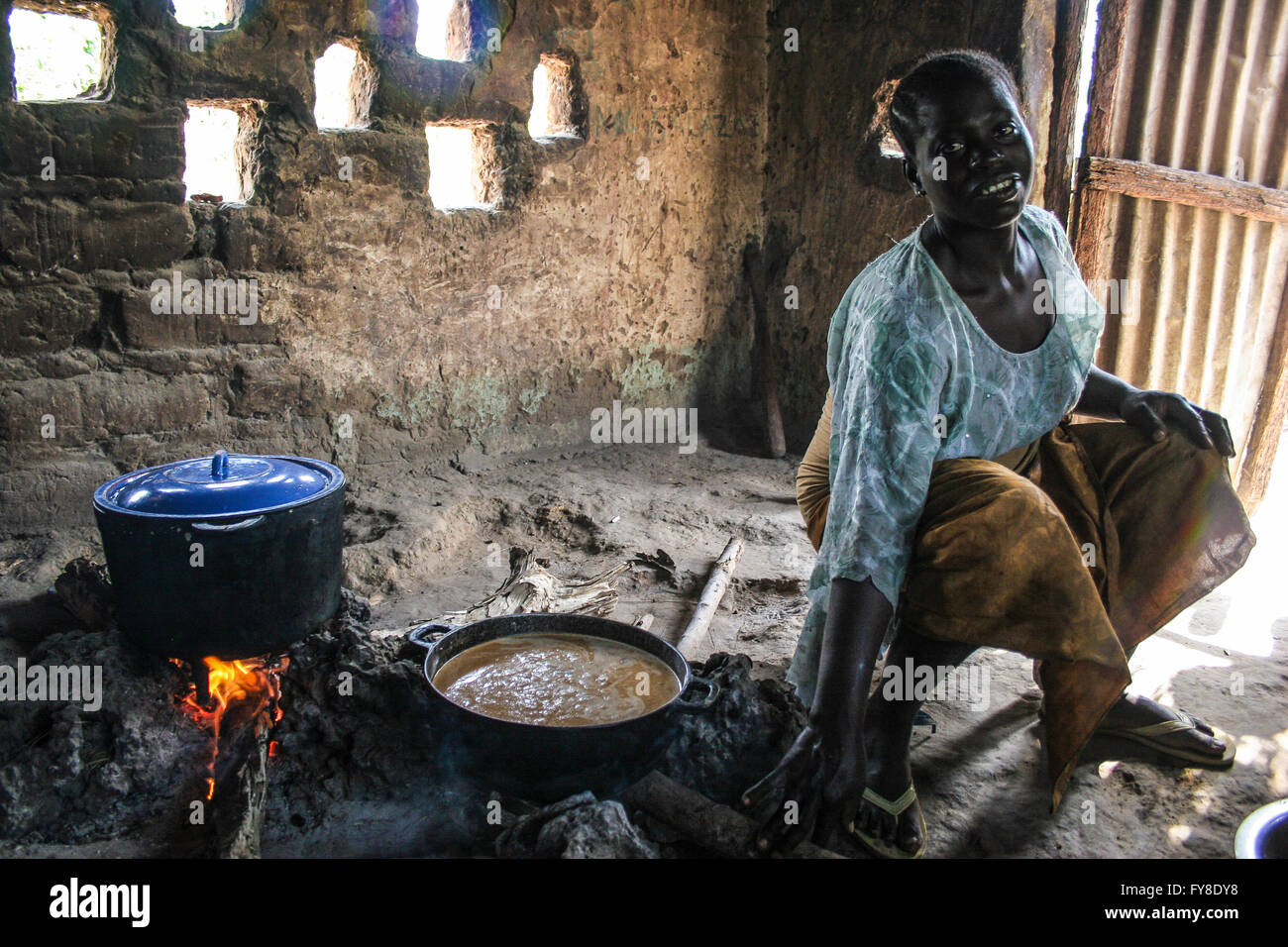 African woman cooking at the kitchen which is situated outside the ...