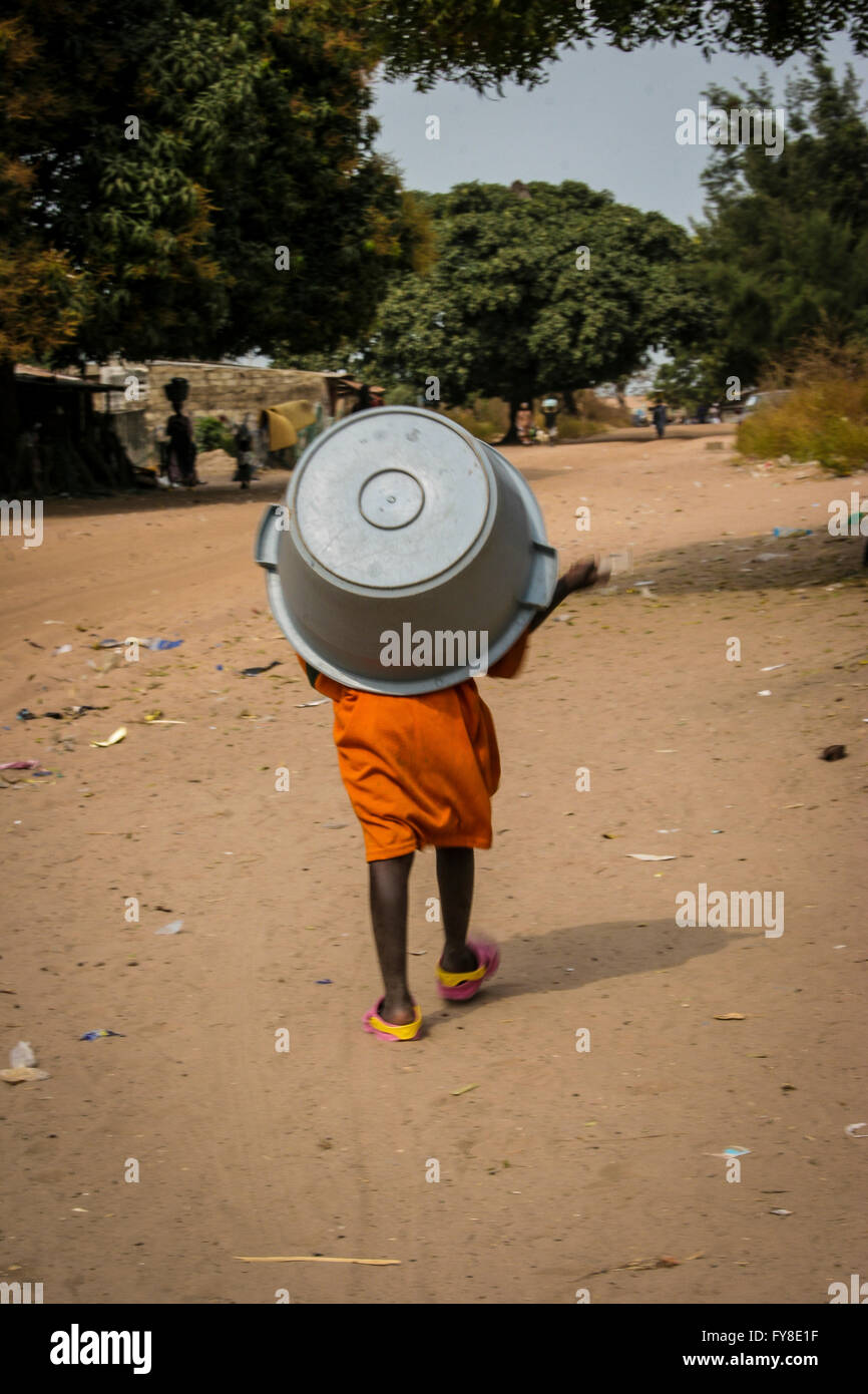 African kid with a bucket on his head providing shade from the sun at ...