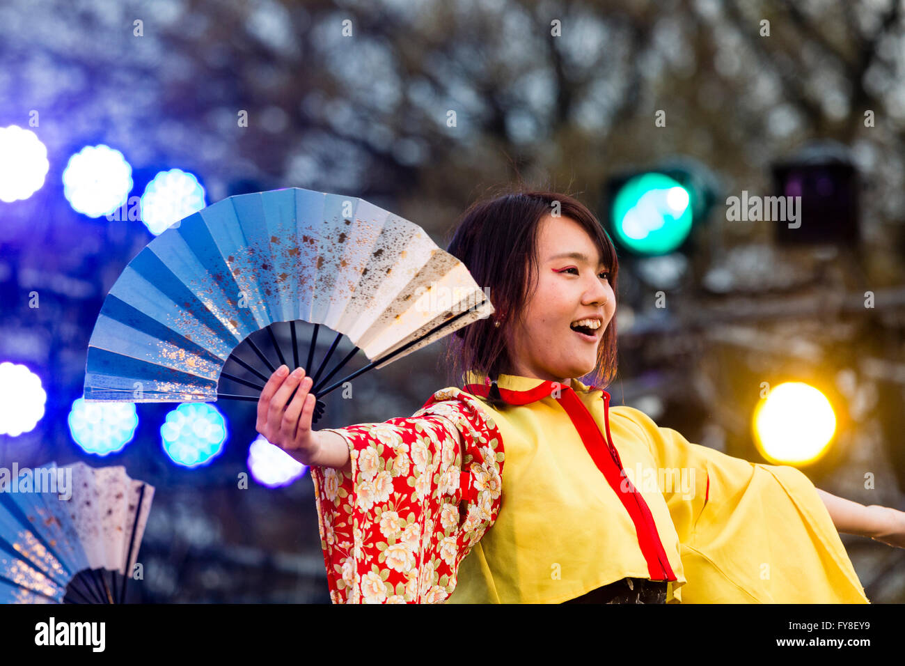 Close up of young Japanese woman dancing while wearing yellow yukata ...