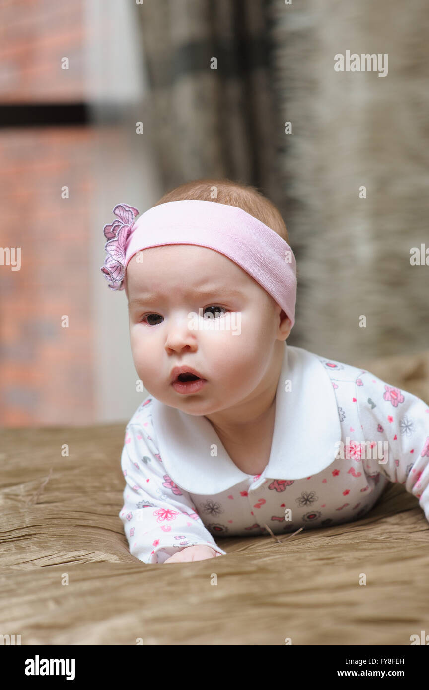Baby girl lying on belly and grimacing Stock Photo - Alamy
