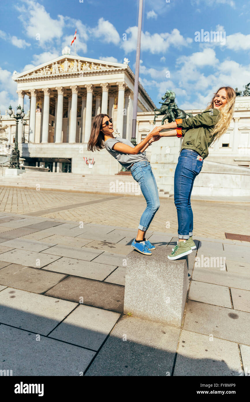 Austria, Vienna, two young women having fun in front of the parliament ...