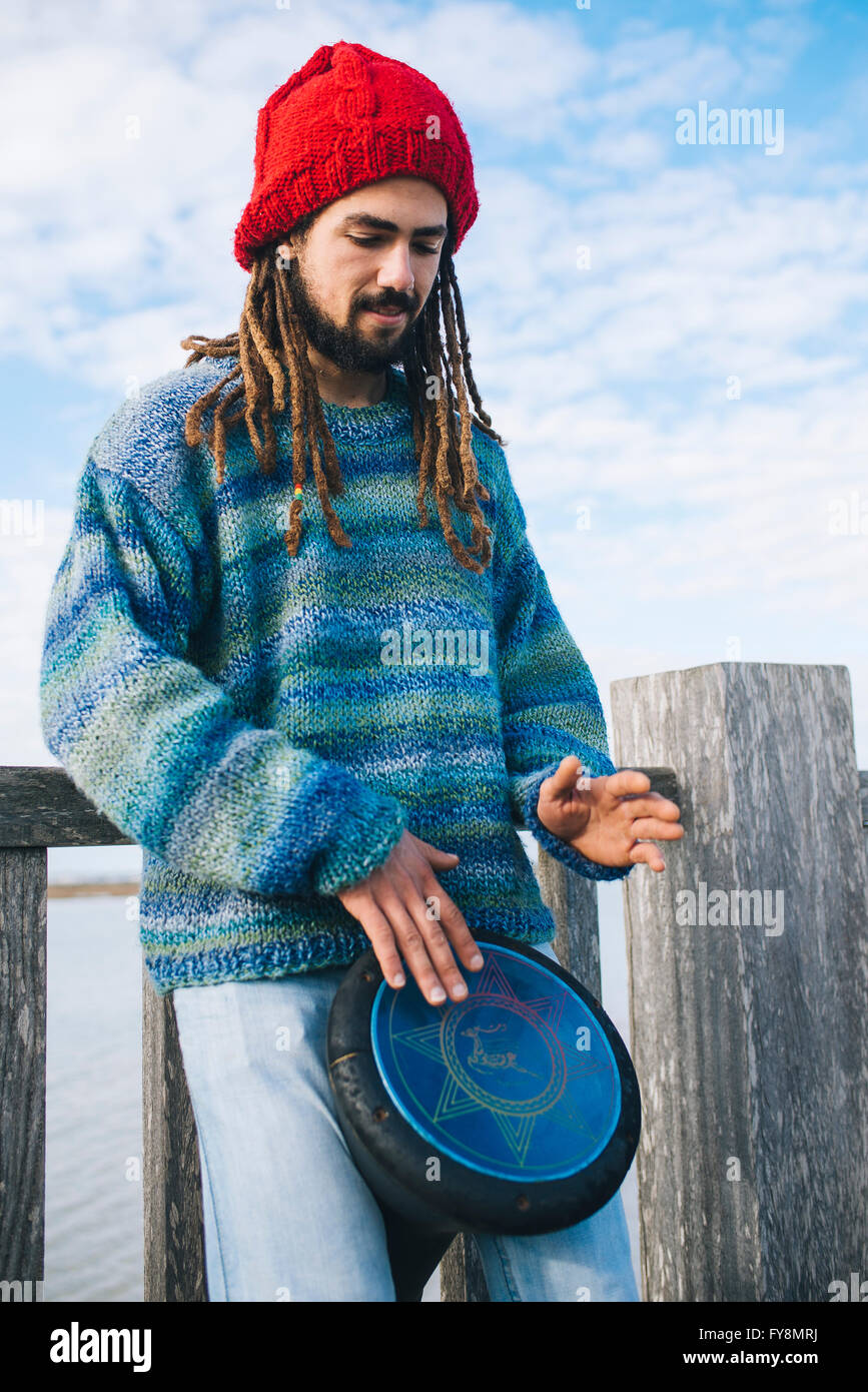 Young man with dreadlocks and wool cap playing a drum Stock Photo - Alamy