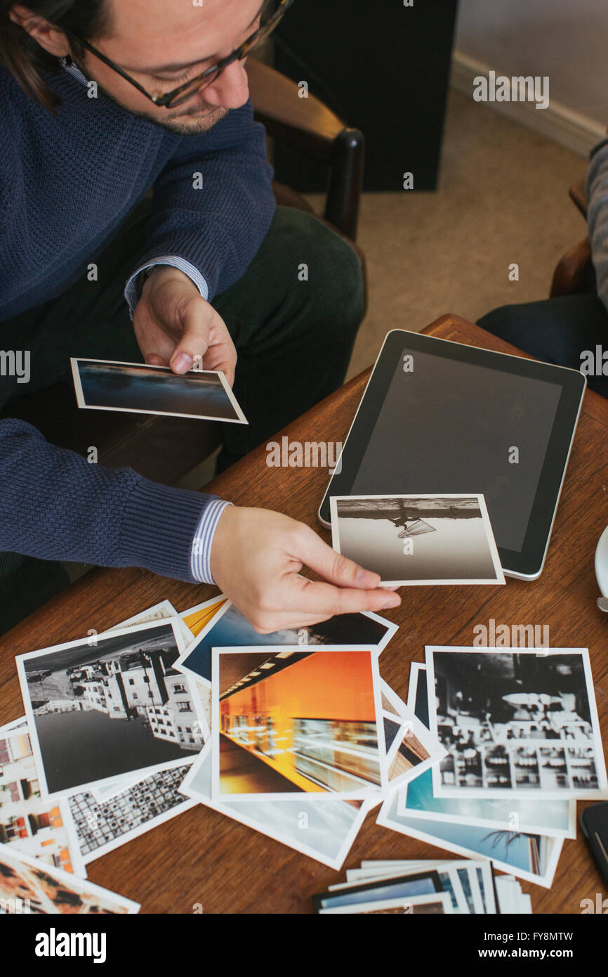 Man in a cafe looking at photo prints Stock Photo - Alamy