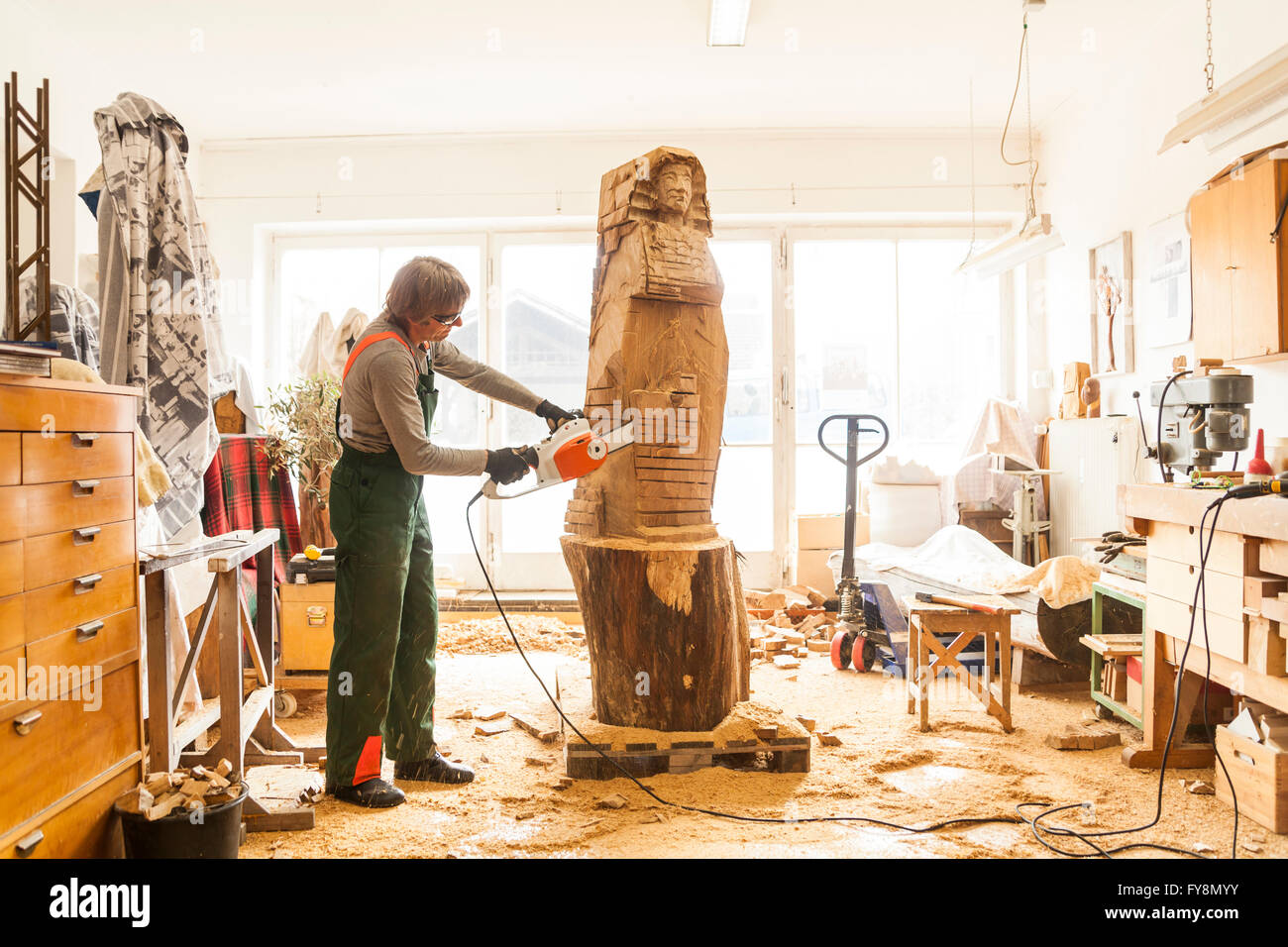 Wood carver in workshop working on sculpture with chainsaw Stock Photo ...