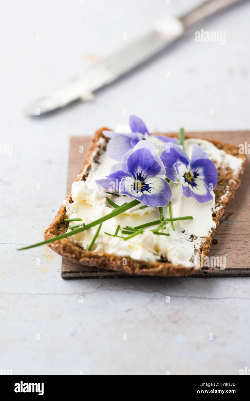 Slice of wholemeal bread with cream cheese, chives and edible Horned ...