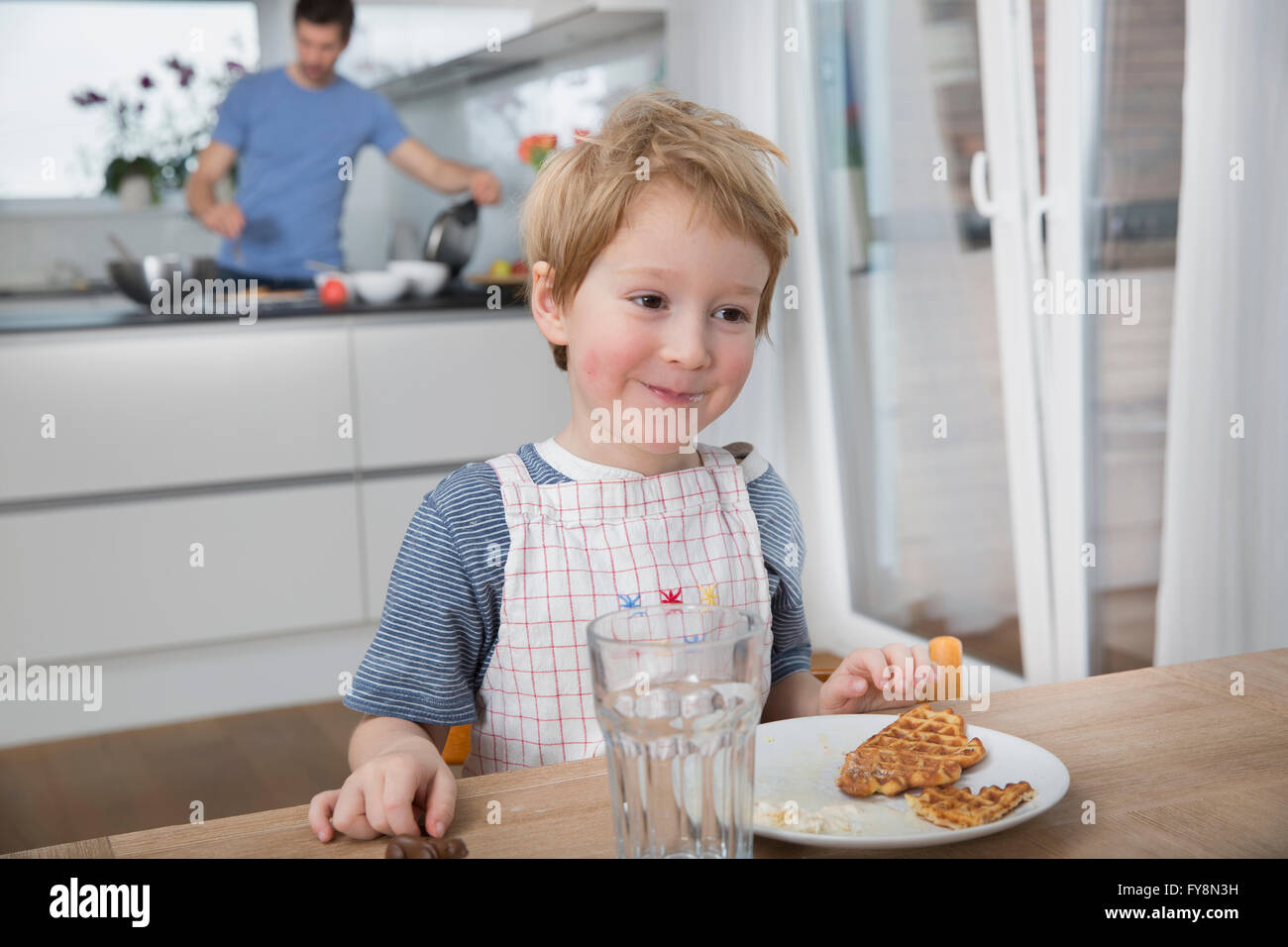 Little boy eating waffles in kitchen Stock Photo - Alamy