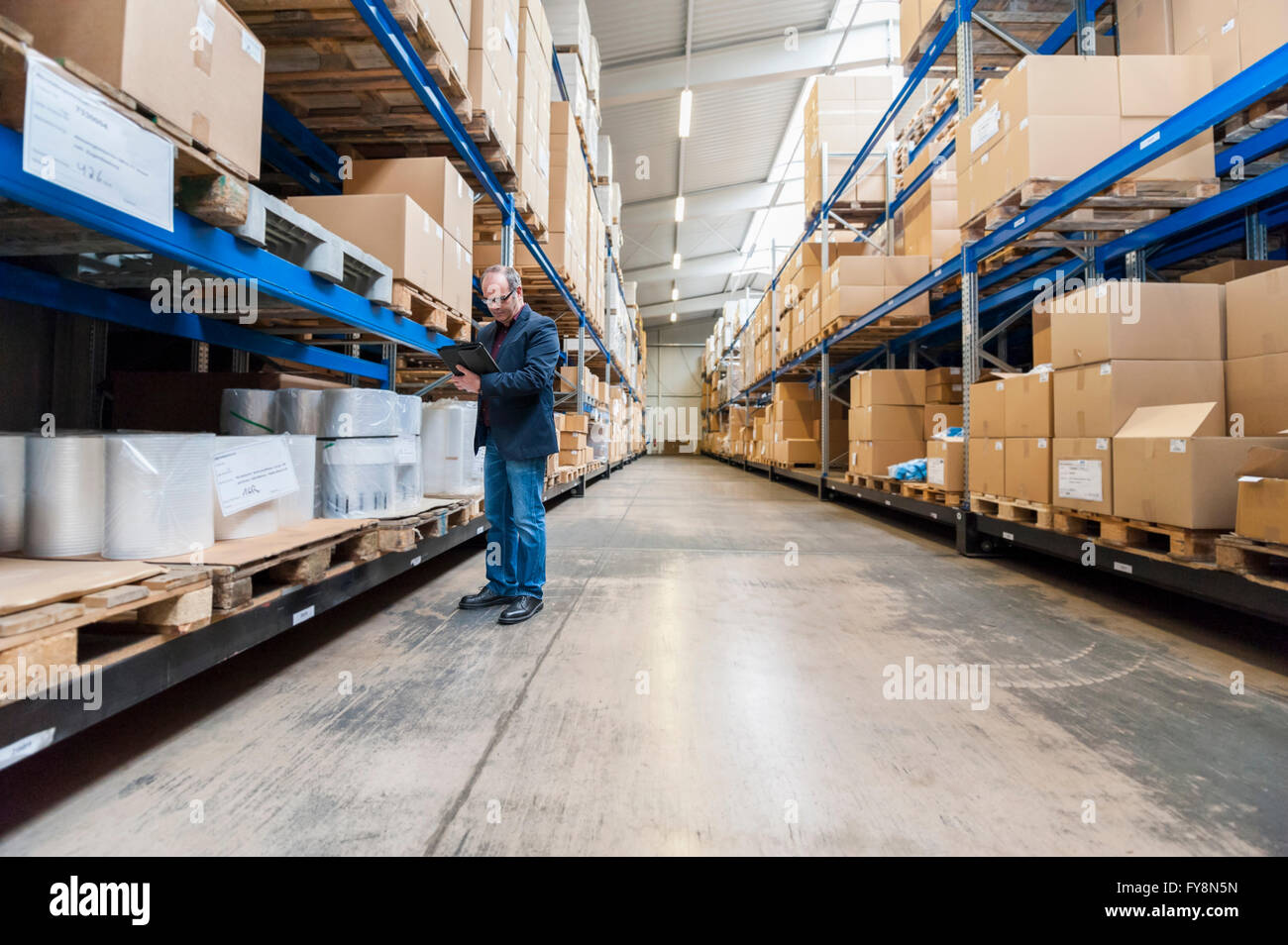 Manager checking goods in storage hall of factory Stock Photo - Alamy