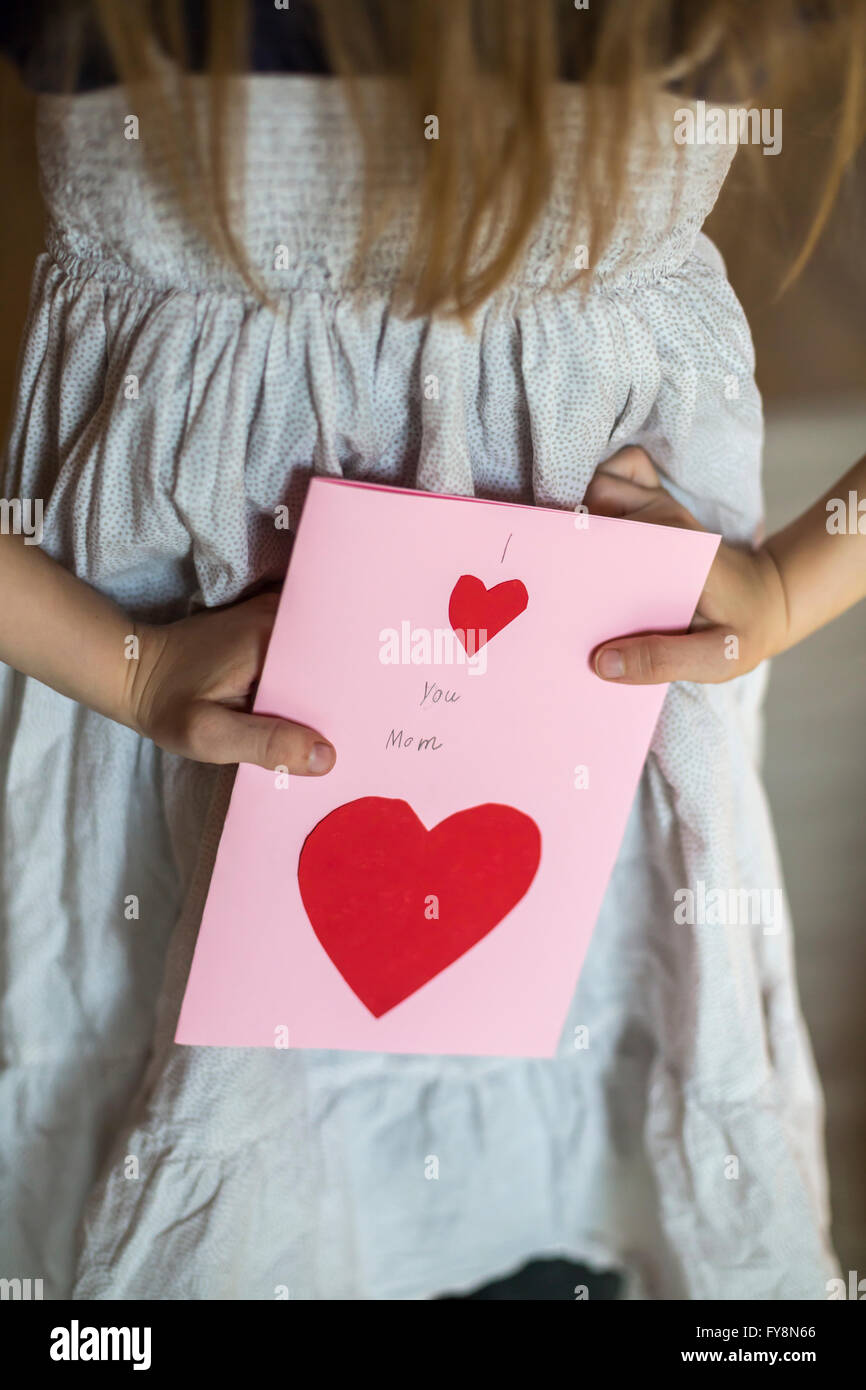 Girl with mother's day card behind back Stock Photo - Alamy