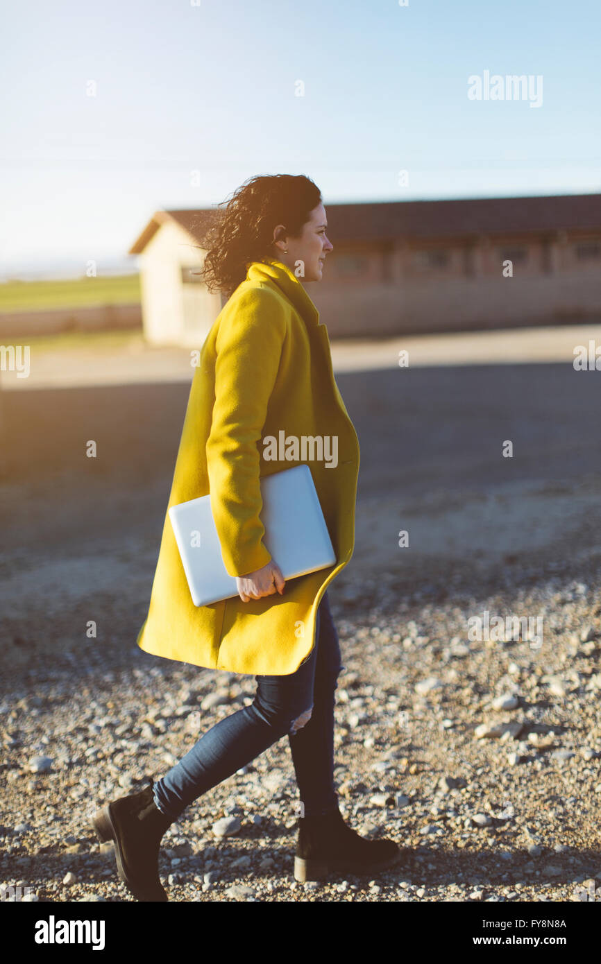 Woman walking with laptop outdoors Stock Photo - Alamy