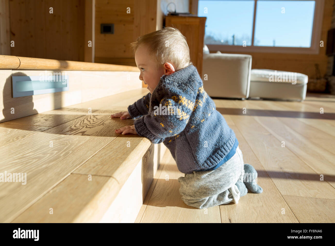 Baby boy crouching on wooden floor looking at his shadow Stock Photo ...