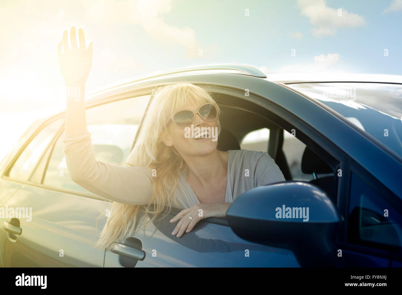Happy woman in car waving Stock Photo - Alamy