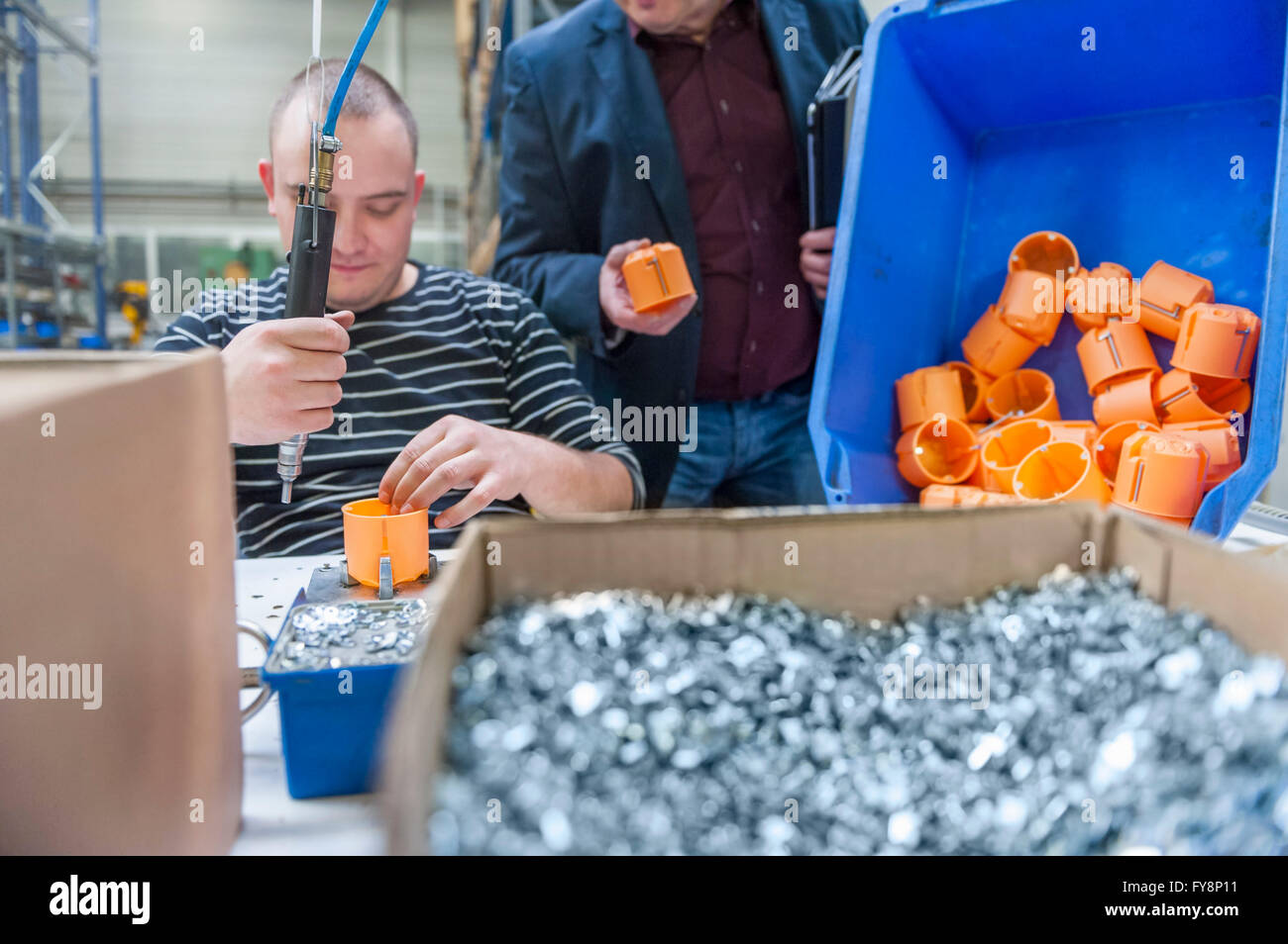 Worker in factory assembling plastic connectors Stock Photo - Alamy