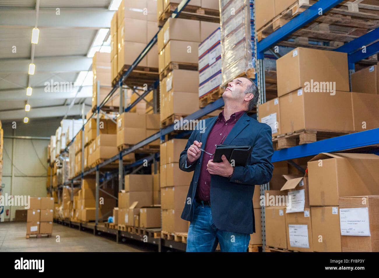 Manager checking goods in storage hall of factory Stock Photo - Alamy