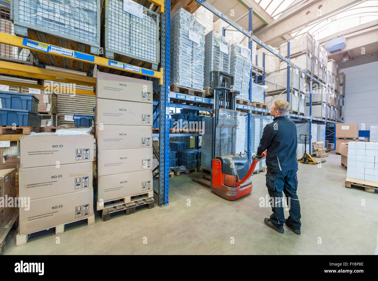 Worker in storage using forklift Stock Photo - Alamy