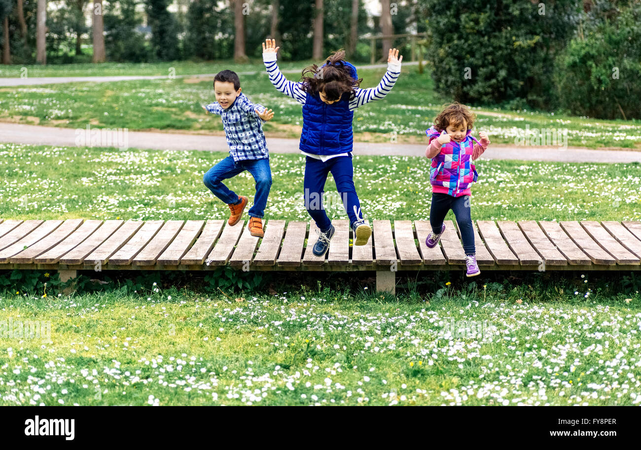 Three children jumping in a park Stock Photo - Alamy