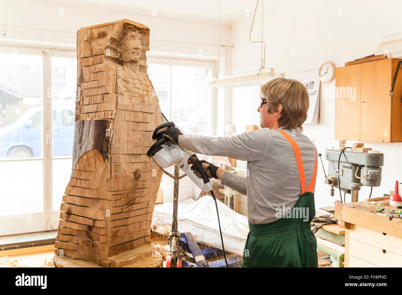 Wood carver in workshop working on sculpture with chainsaw Stock Photo ...