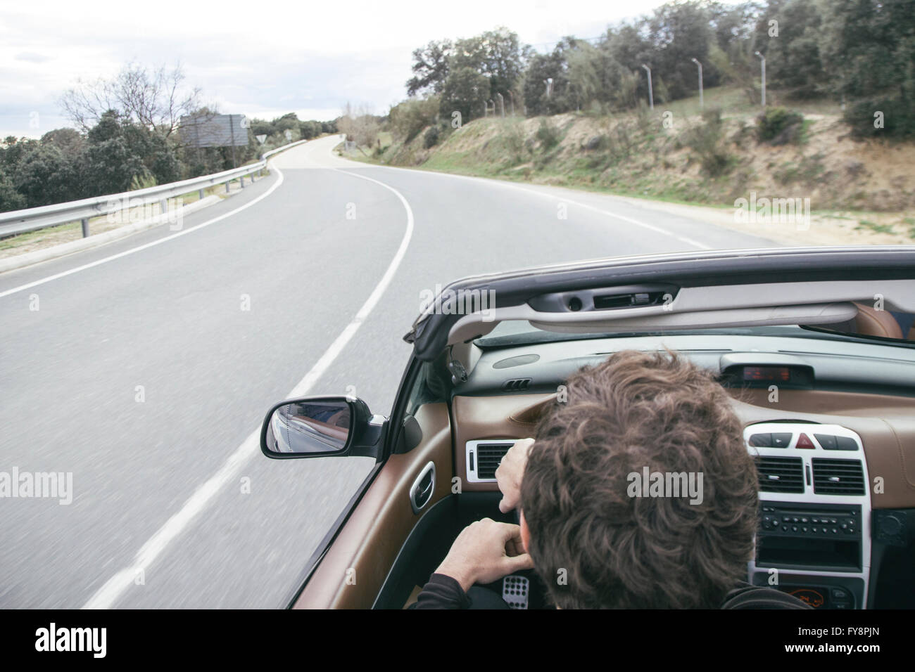 Man driving a convertible car on empty country road Stock Photo - Alamy
