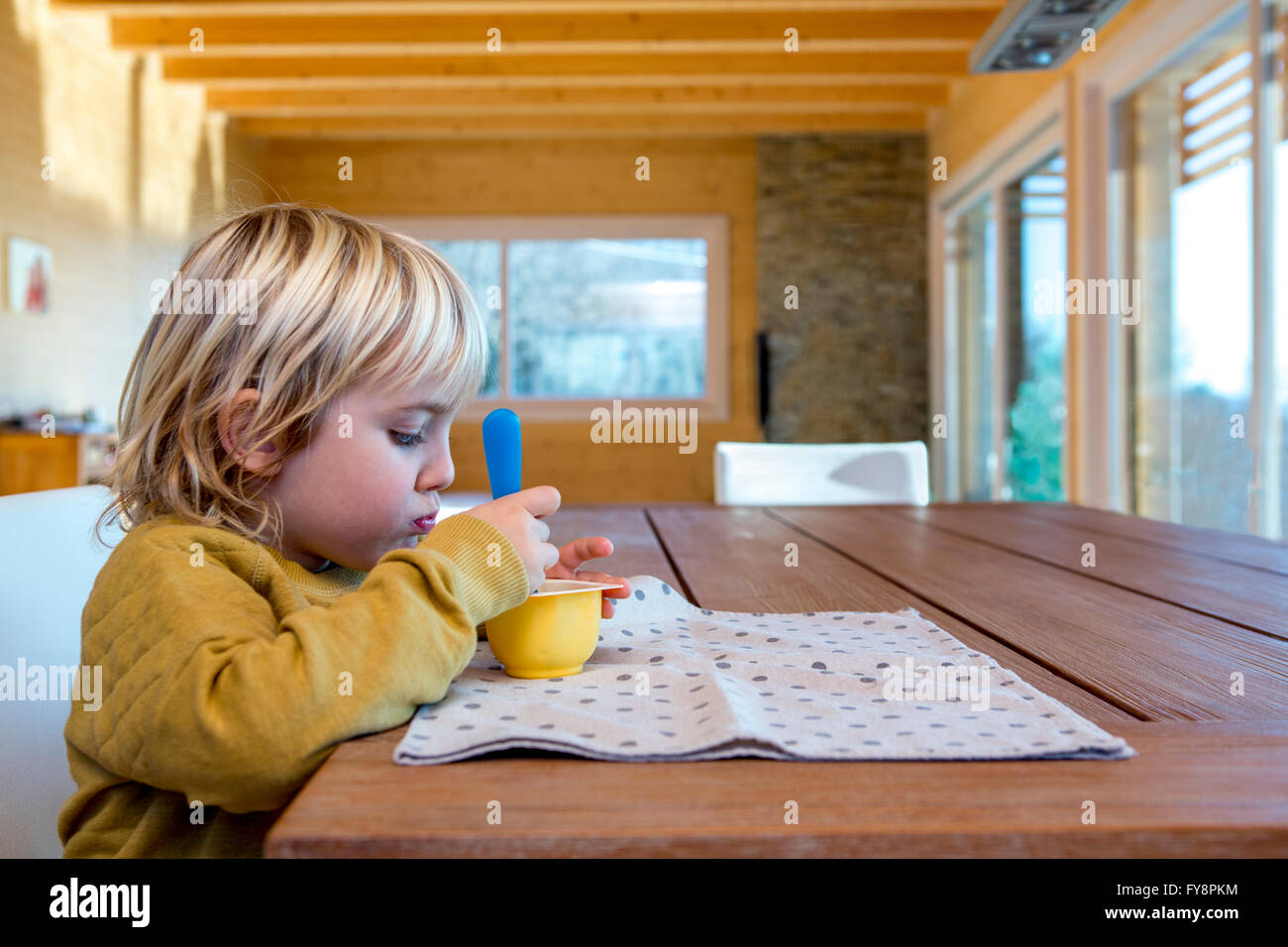 Little boy sitting at wooden table eating something Stock Photo - Alamy
