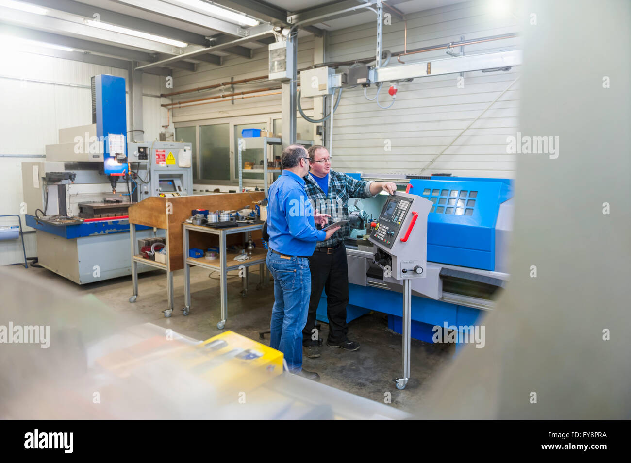 Two men in factory talking at machine for mold making Stock Photo - Alamy