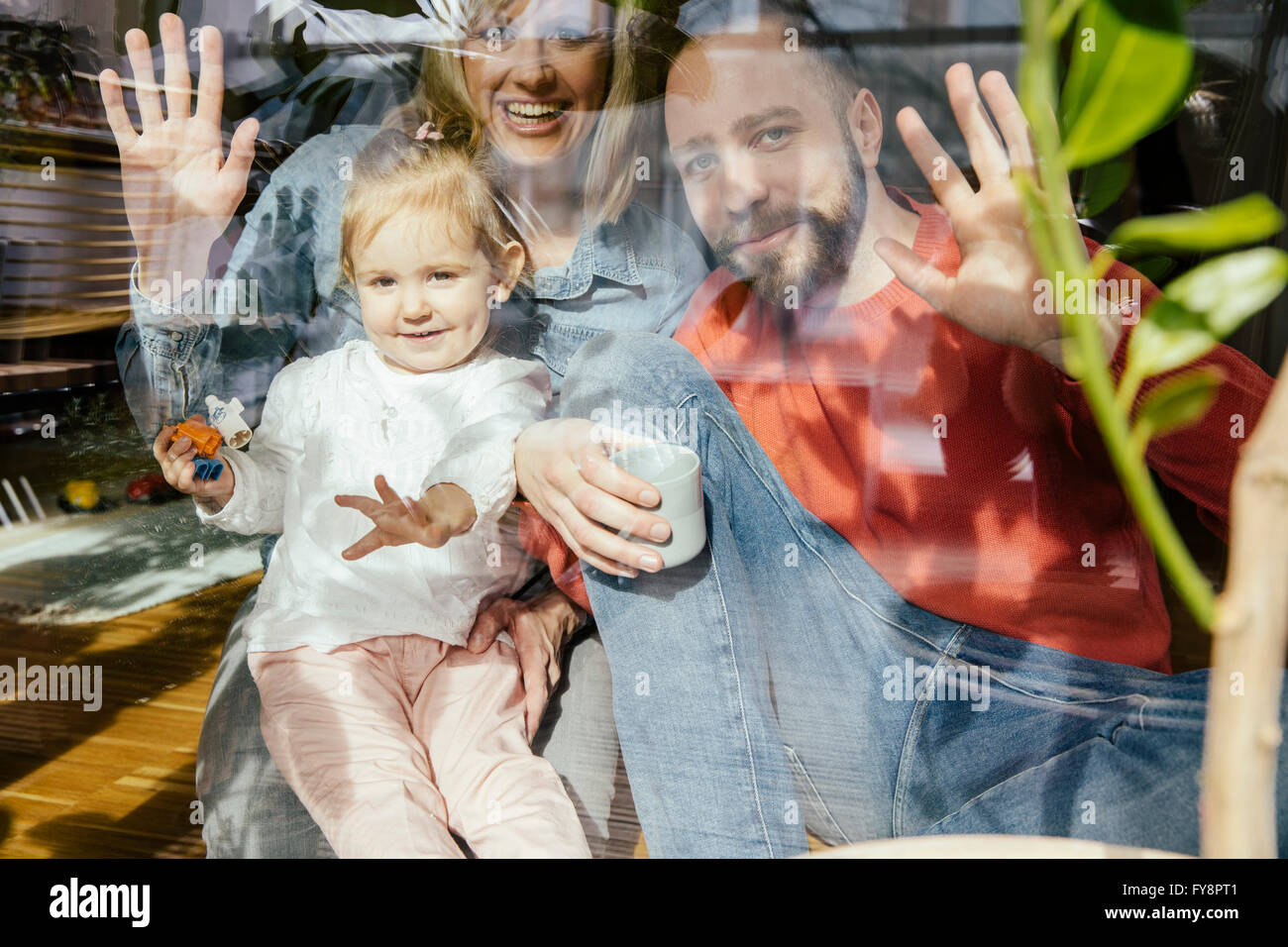 Mother, father and little girl waving out of window Stock Photo - Alamy