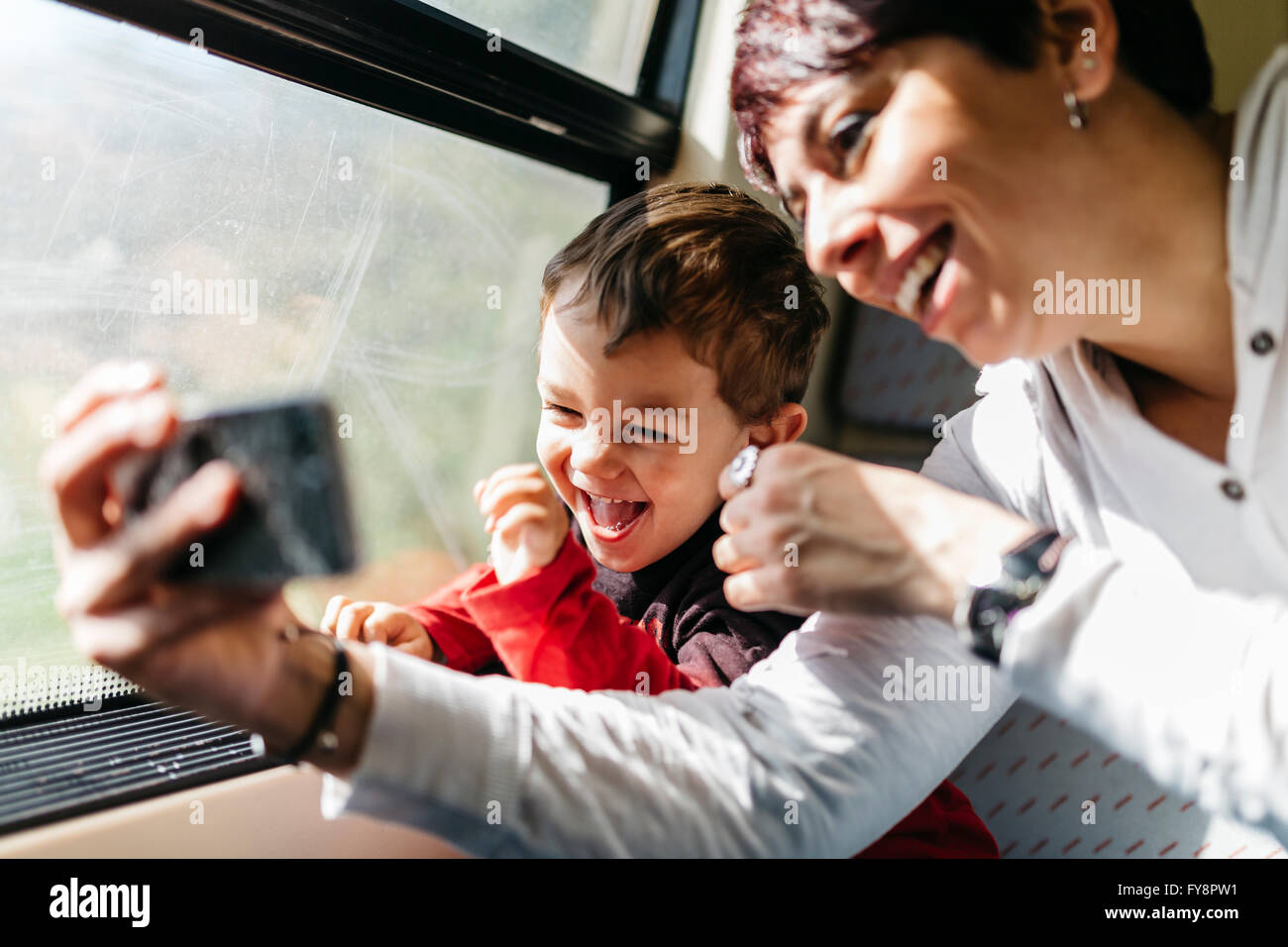 Happy little boy on his first train ride having fun with his mother ...