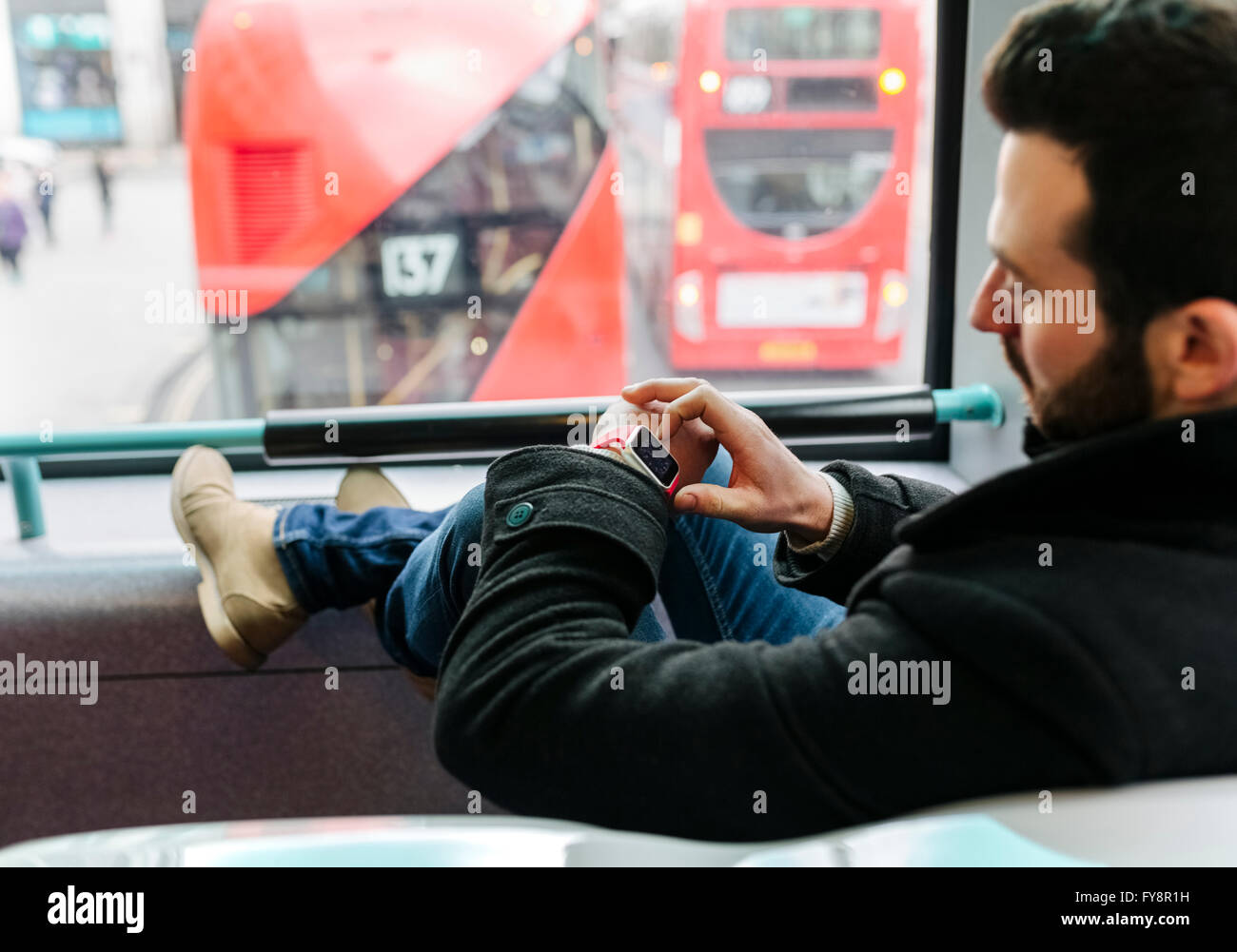 UK, London, young man in a double-decker bus using his smartwatch Stock ...