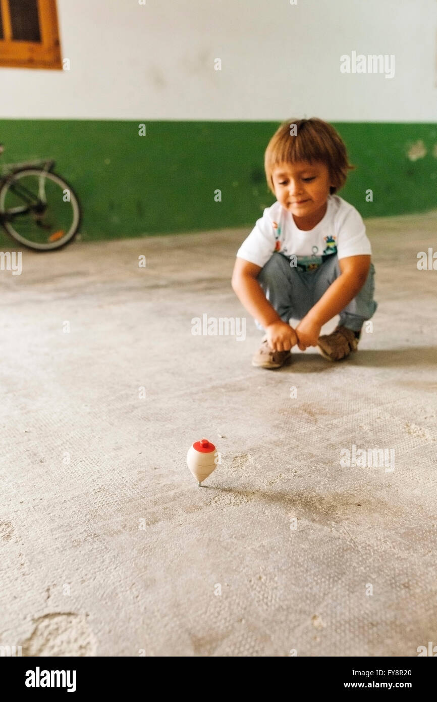 Smiling little boy watching spinning top Stock Photo - Alamy