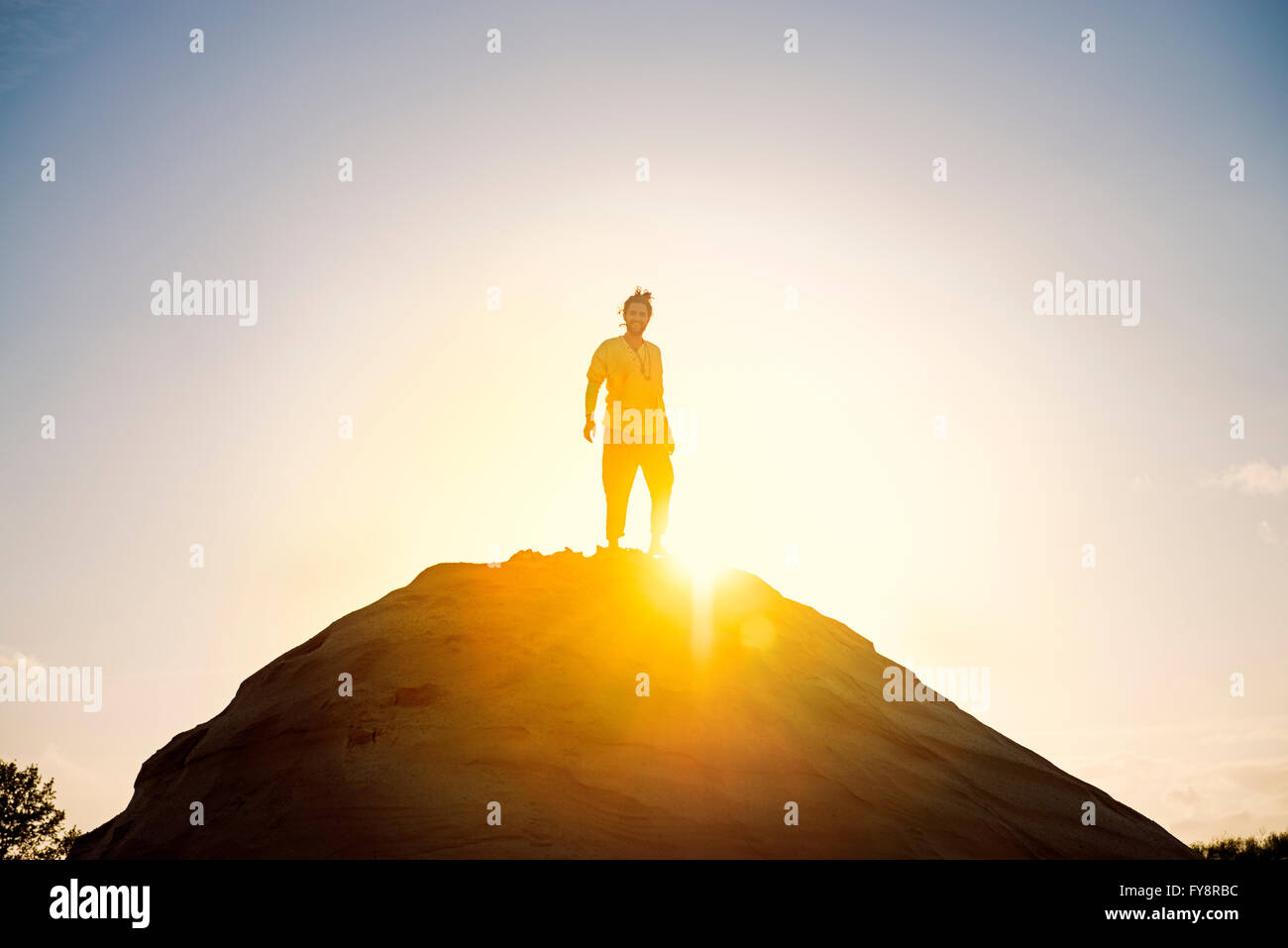 Man standing on hill against sunset Stock Photo - Alamy