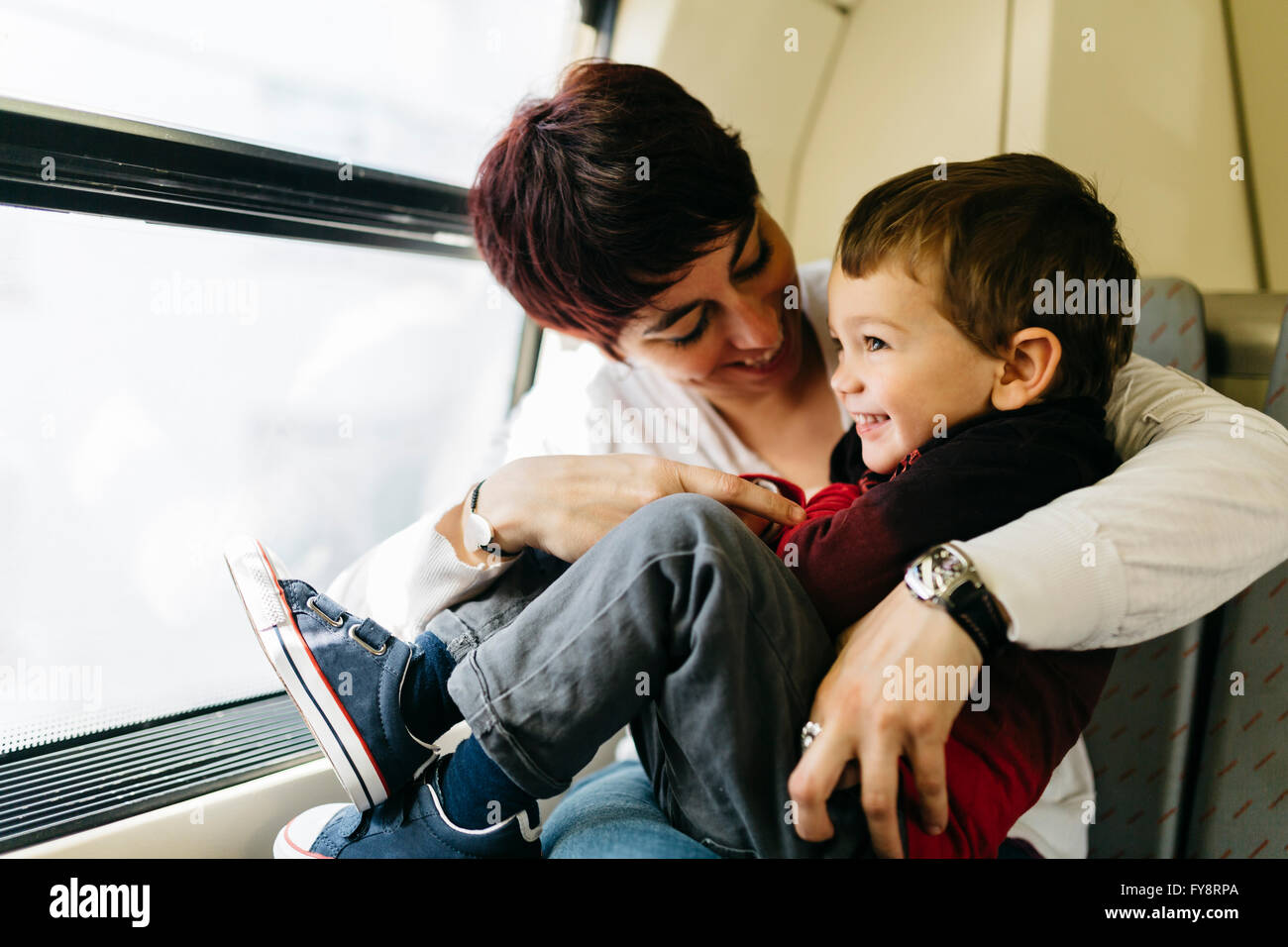 Happy little boy on his first train ride having fun with his mother ...