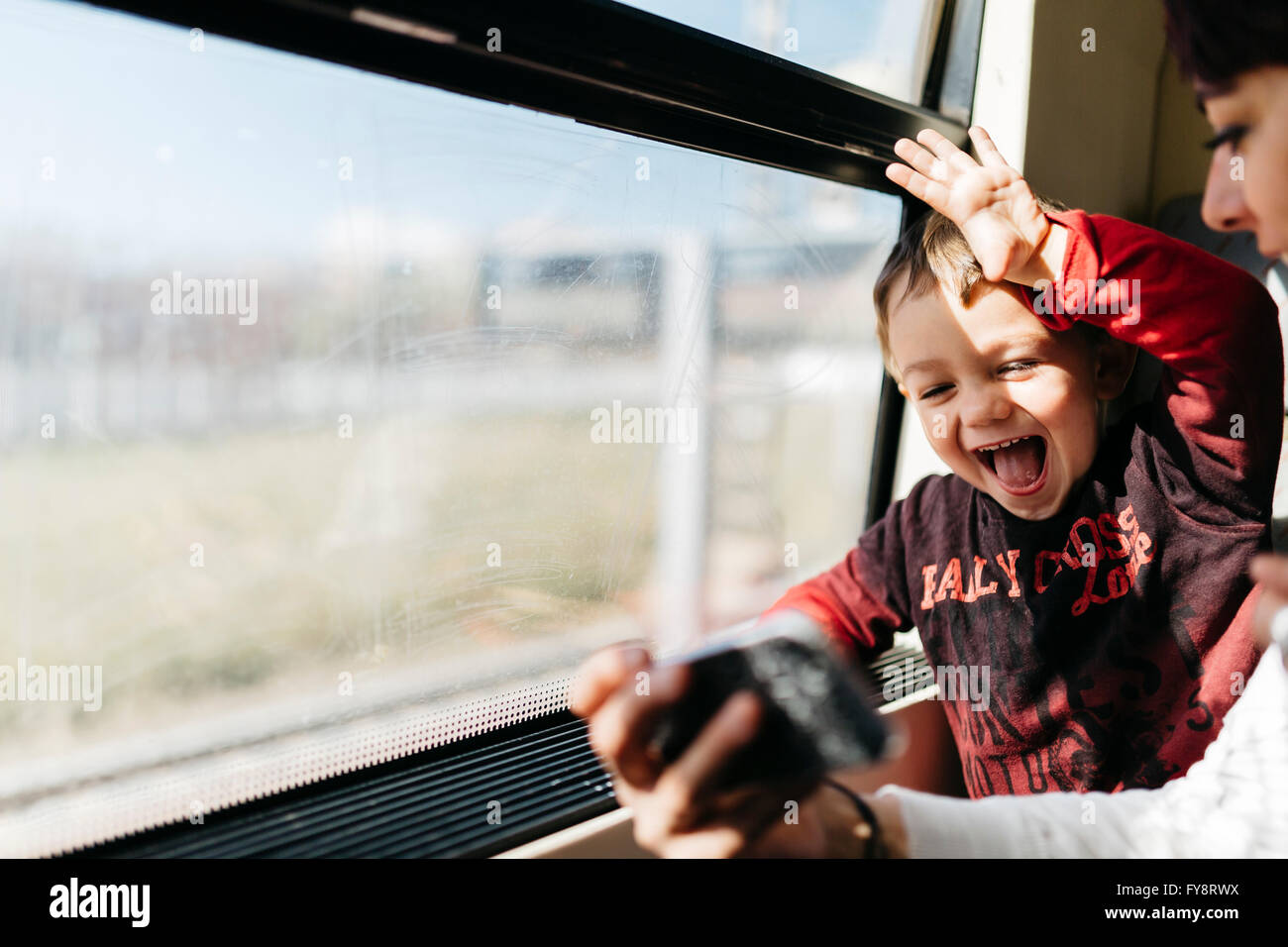 Happy little boy on his first train ride having fun with his mother ...
