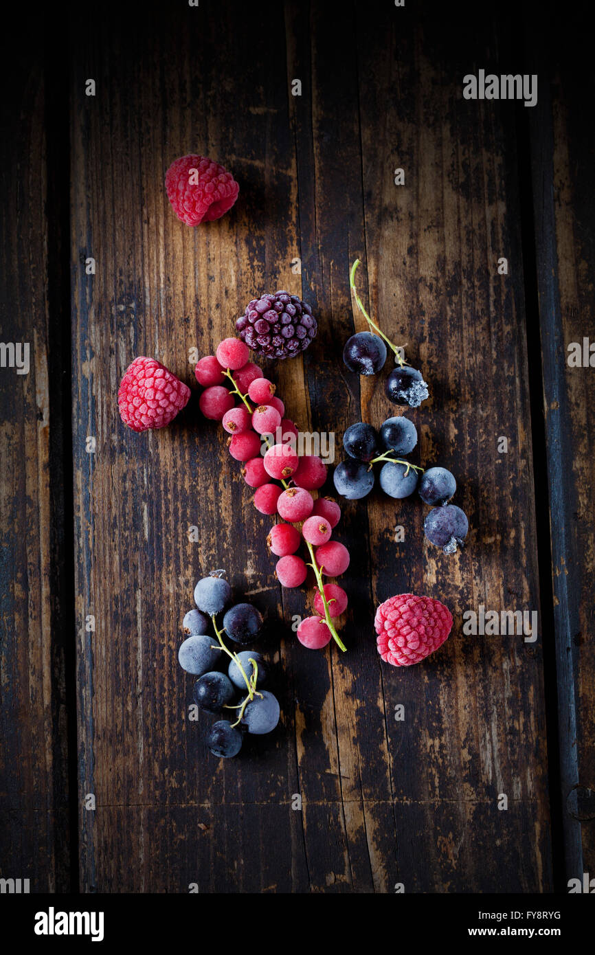 Deep frozen red and black currents, rasberries and blackberries on wood ...
