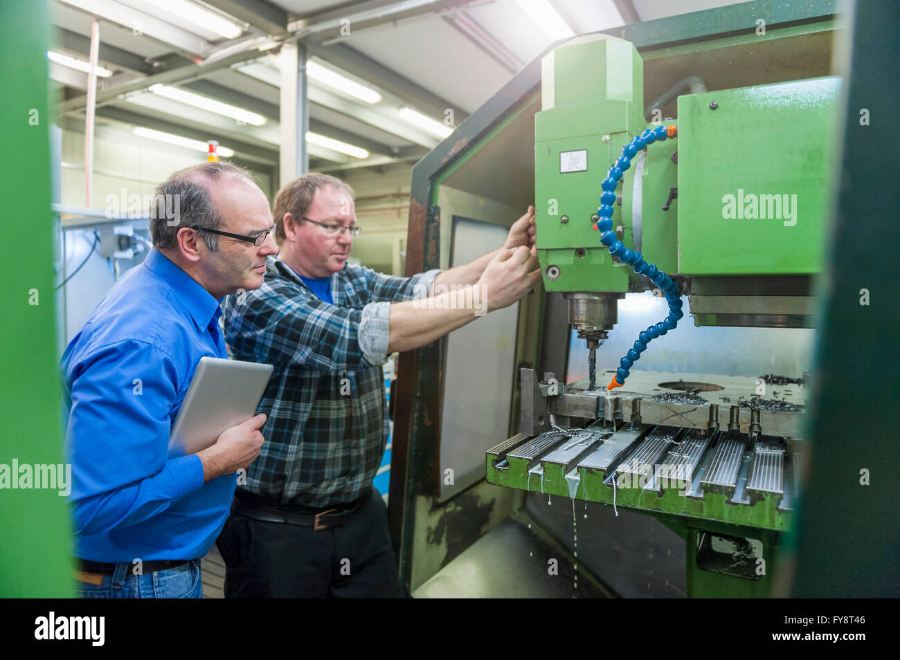 Two men in factory at a steel drill machine Stock Photo - Alamy