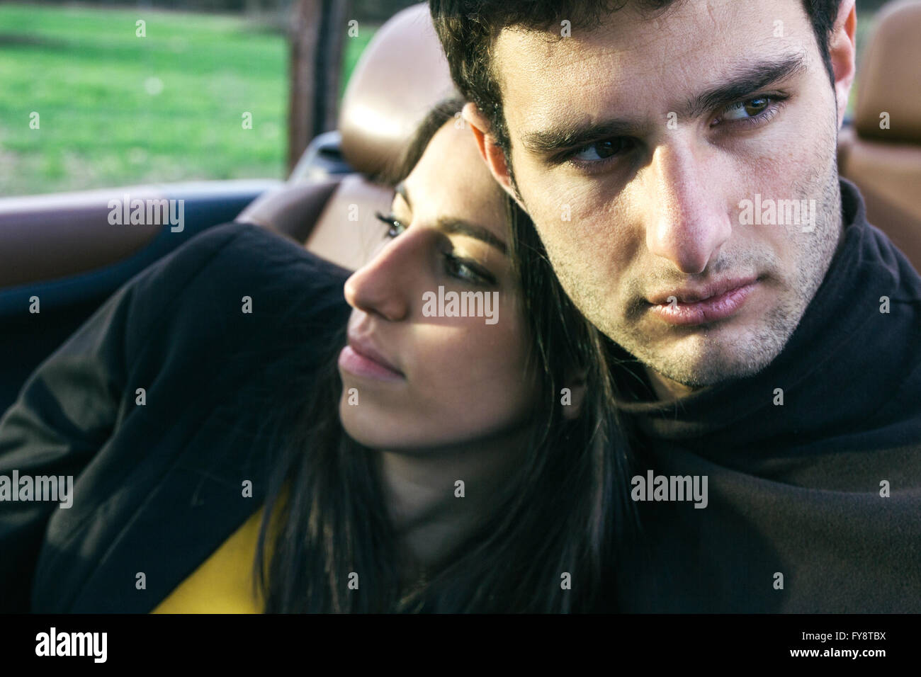 Portrait of young man sitting with his girlfriend in a convertible ...