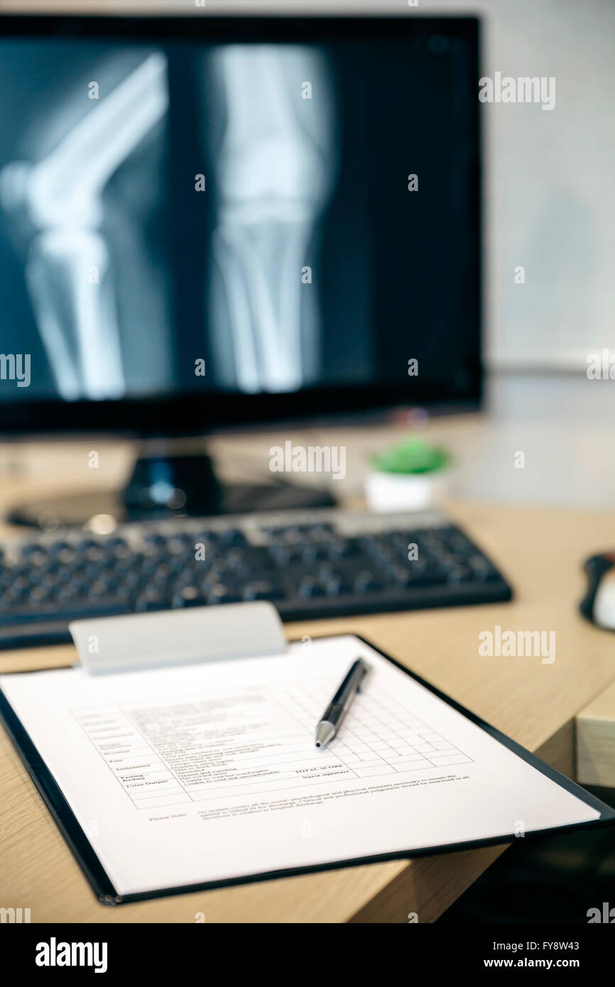 Close-up of medical report on table and x-ray image on computer screen ...