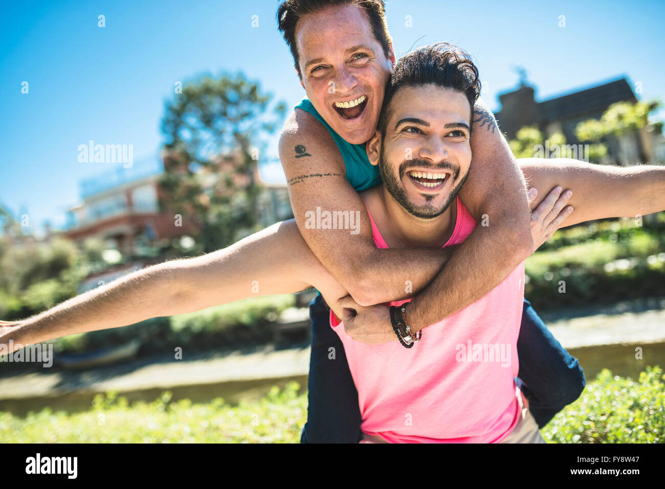 Laughing man carrying his boyfriend piggyback Stock Photo - Alamy