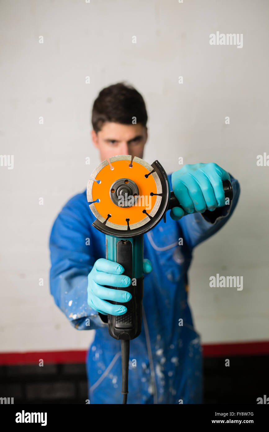 Construction worker showing an angle grinder Stock Photo - Alamy