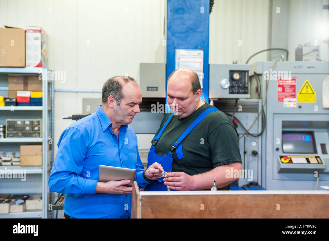 Two men in factory talking in a factory Stock Photo - Alamy