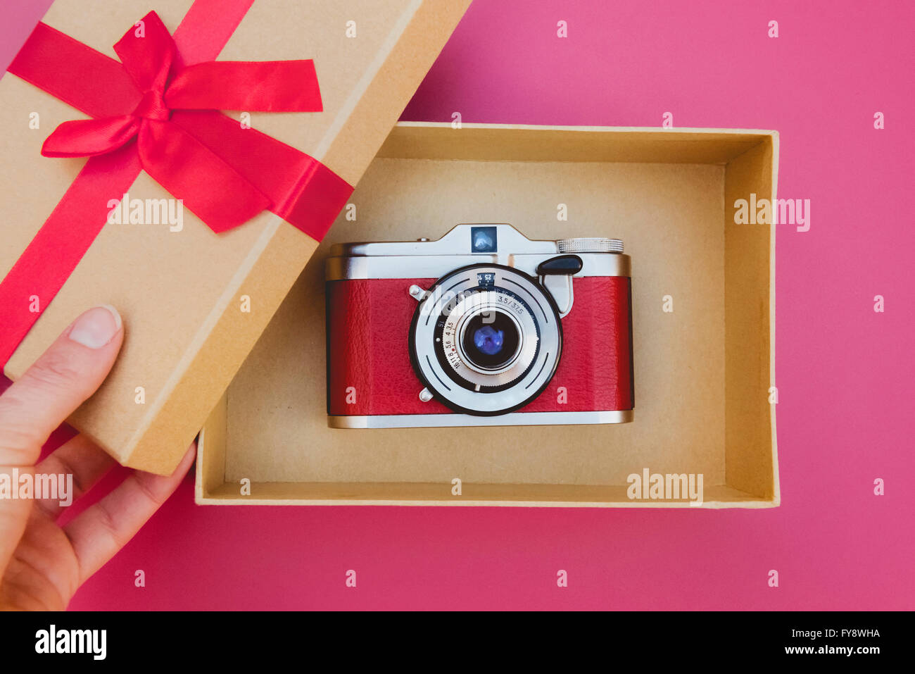 Woman's hand opening a gift box with a beautiful analog camera inside ...
