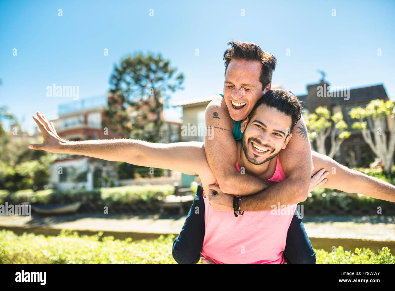Laughing man carrying his boyfriend piggyback Stock Photo - Alamy